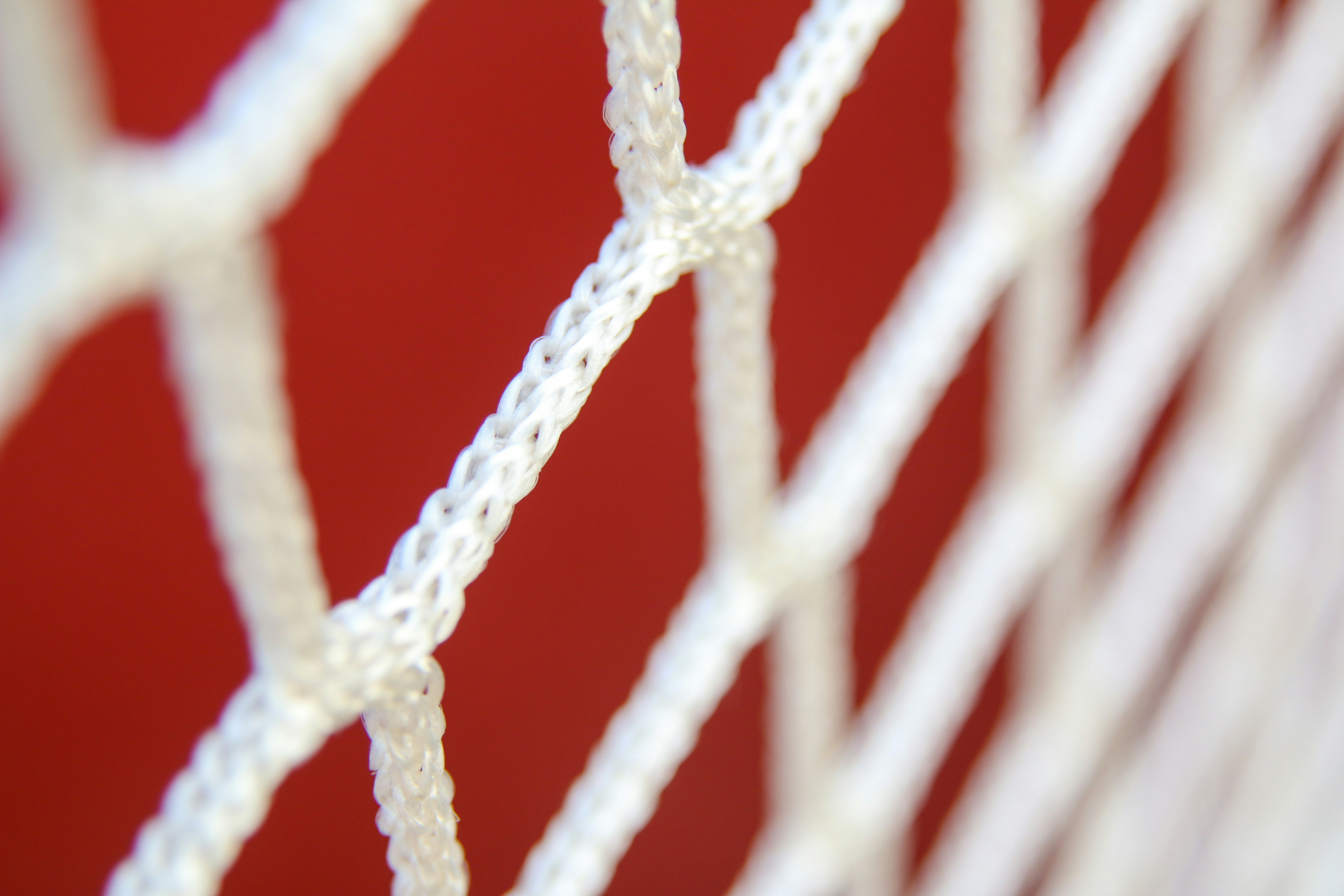 Tangled Web: Close-up of White Rope Net Against Bold Red Backdrop
