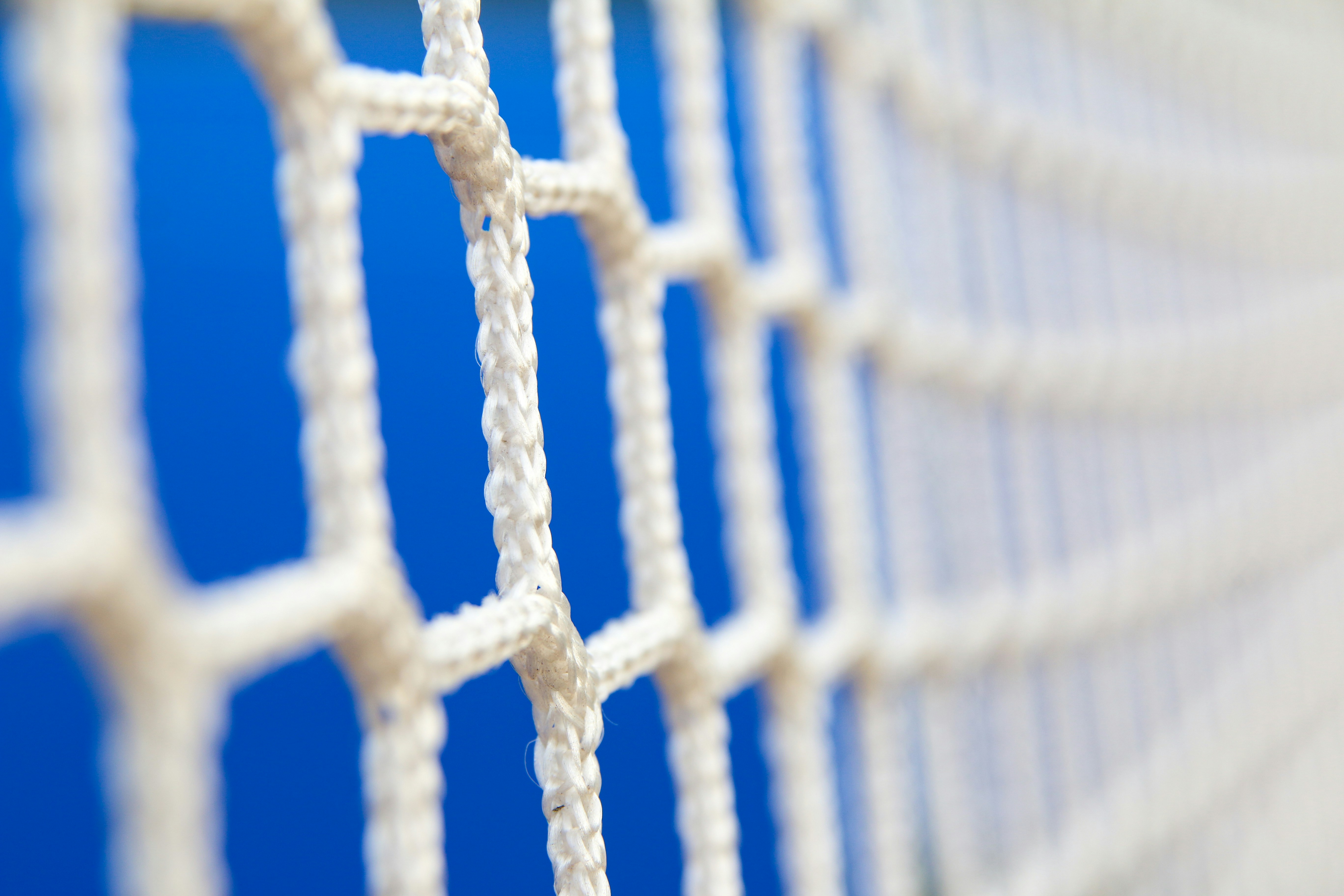 Tethered Haze: close-up of a rope net receding into blue depth
