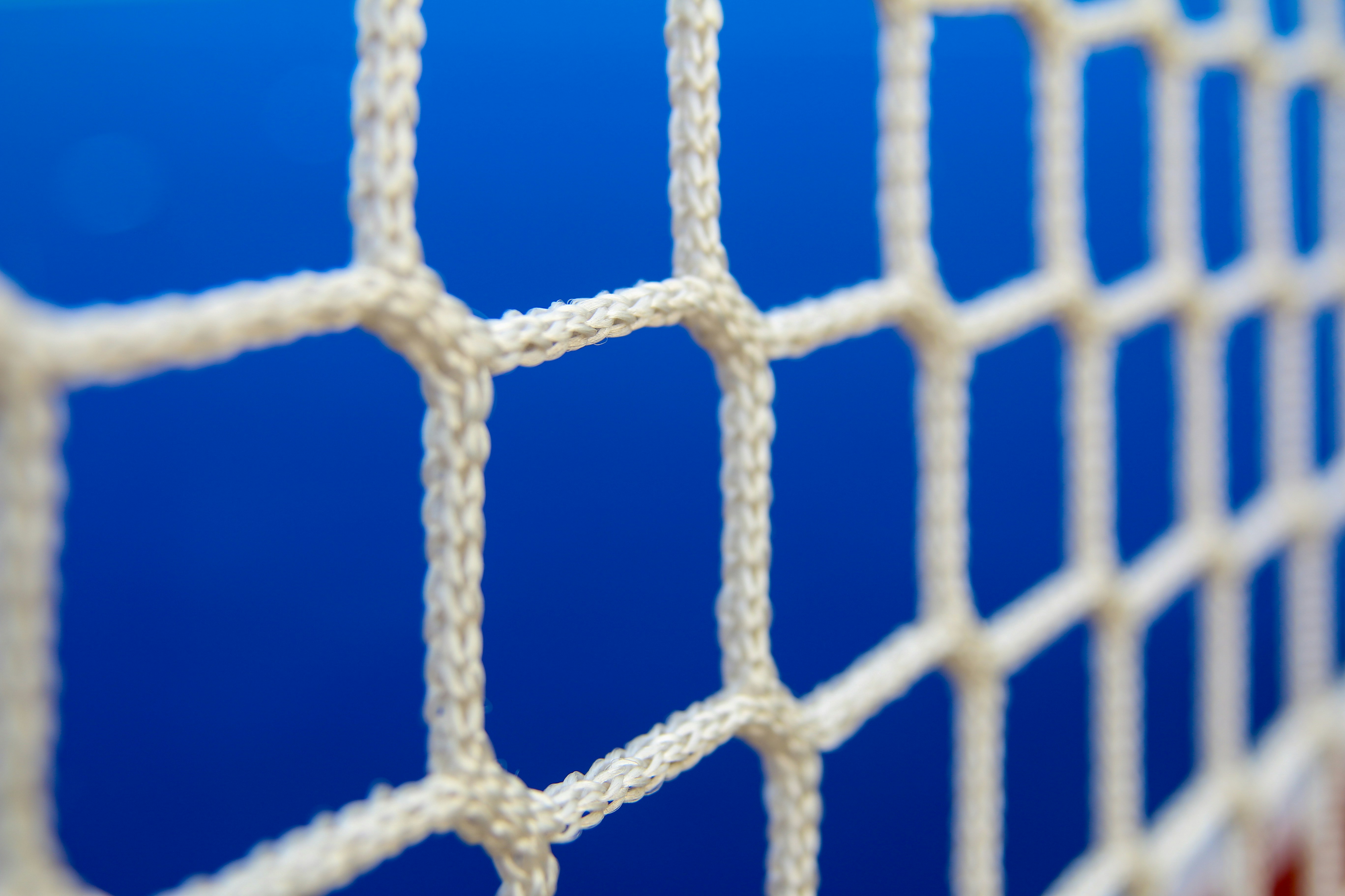 Gridwork of Focus: A Close-Up on Rope Netting Against a Deep Blue Void