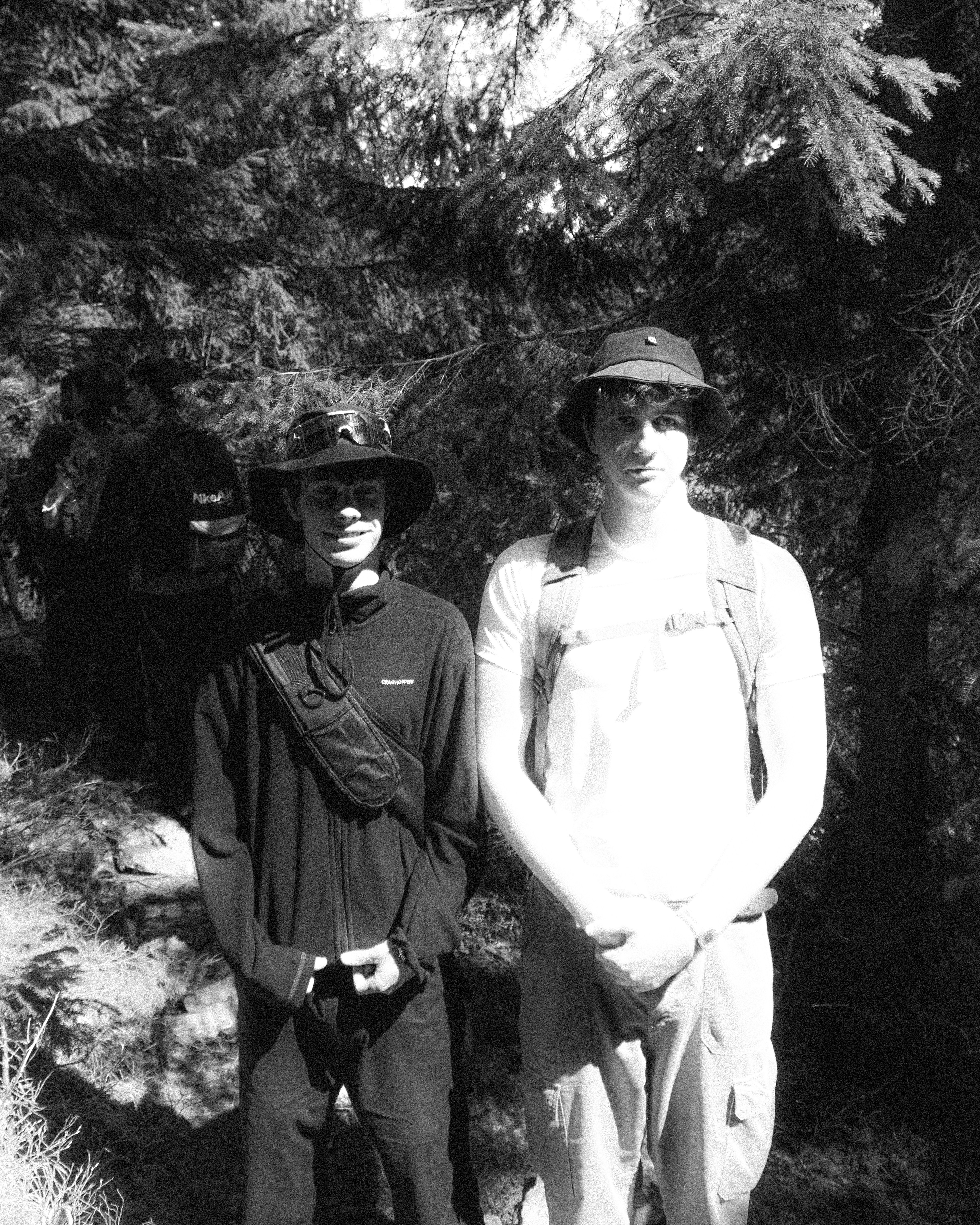 Two hikers in a shaded forest, faces brightened by sunlight