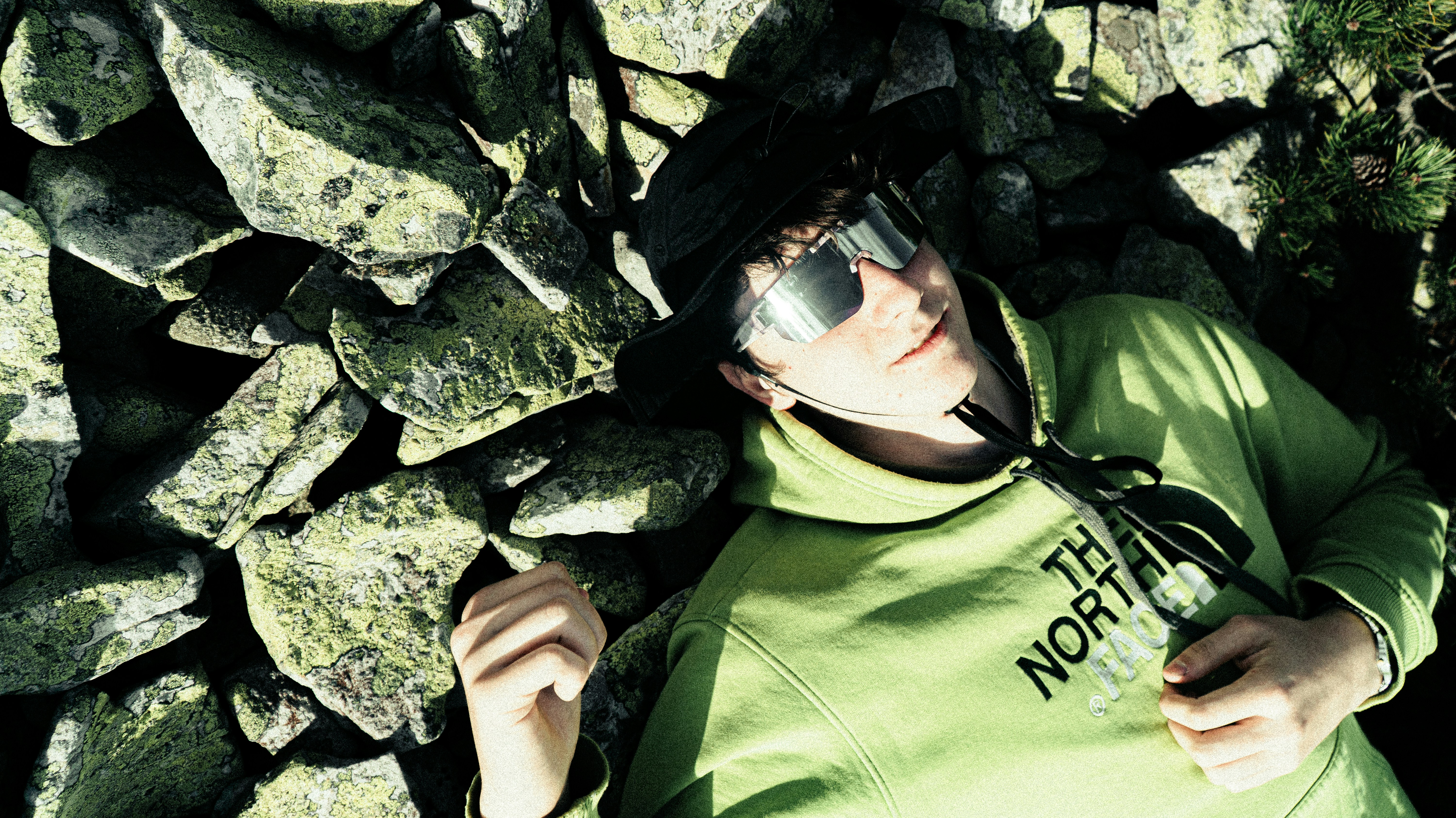 Neon-green hoodie under rock canopy with mirrored Sunglasses
