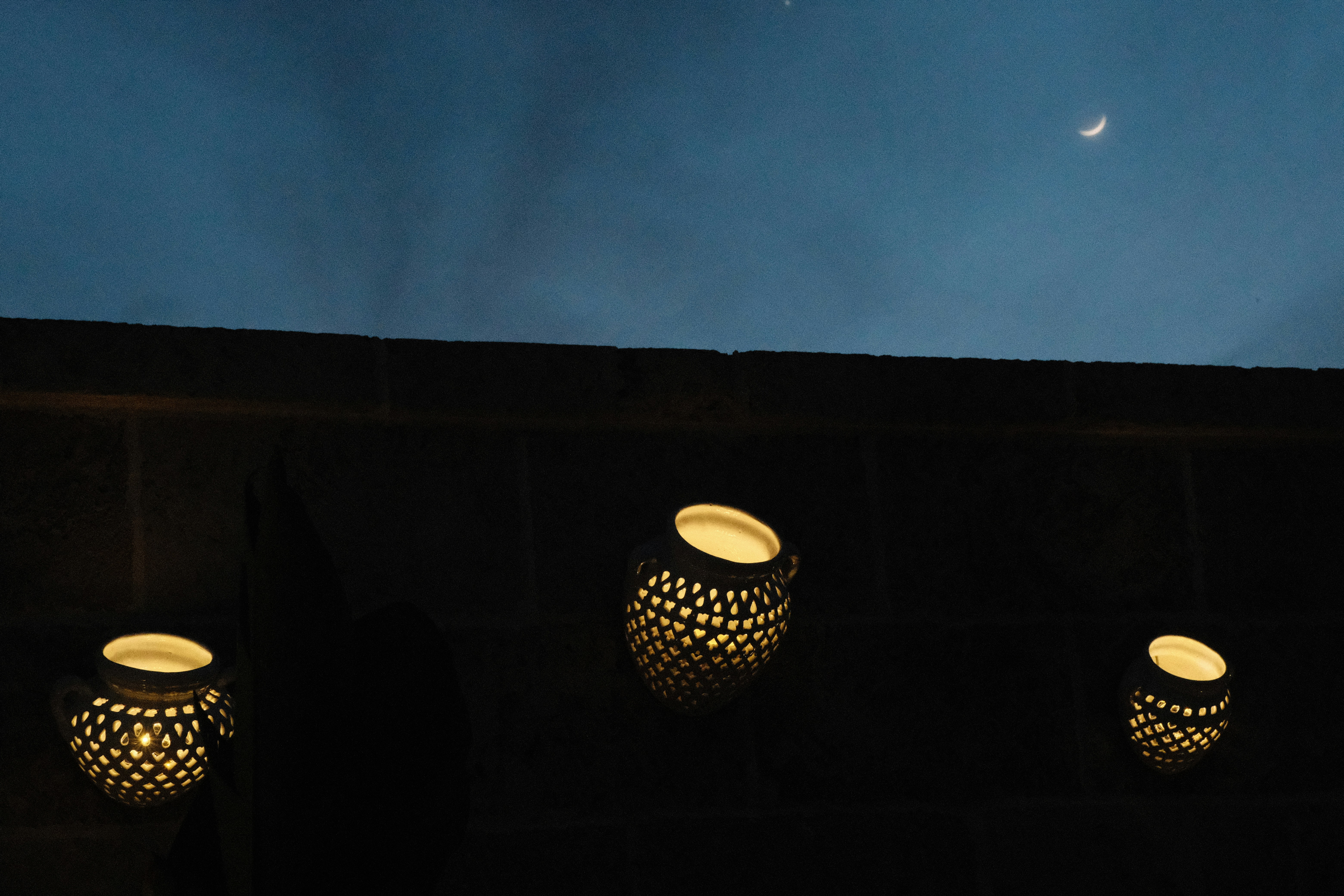 Decorative lanterns glow under a dark sky and crescent moon.
