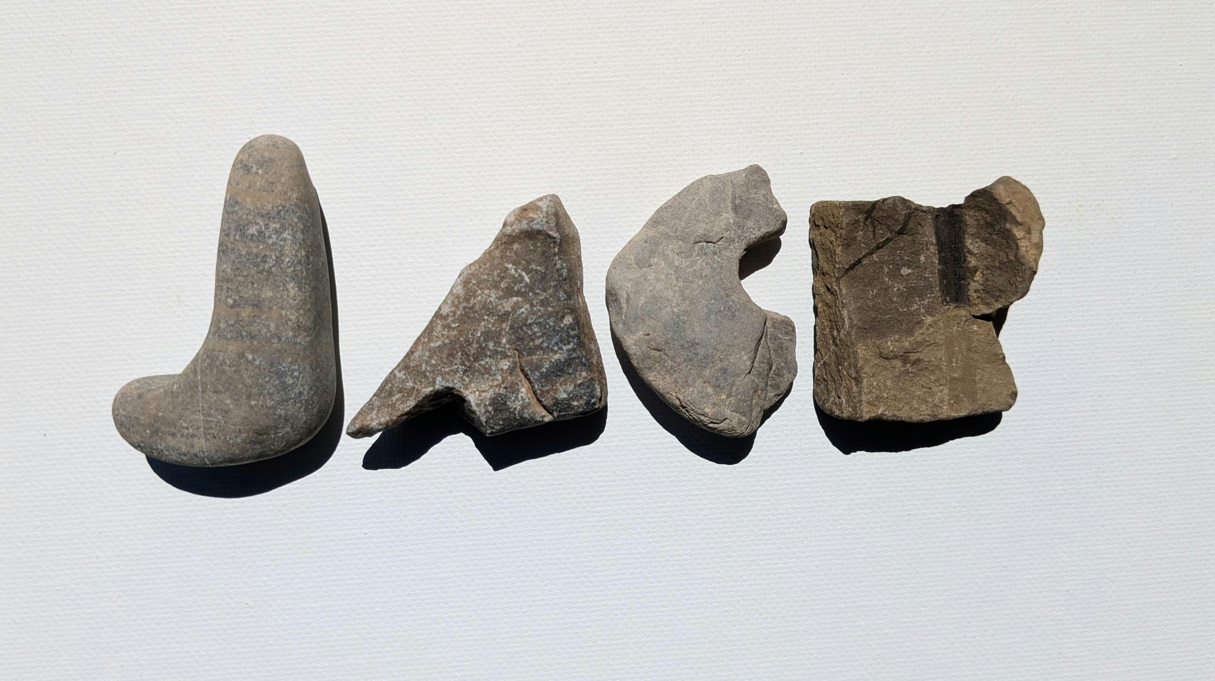 Rock-lettering: Four Stones Spelling 'HACK' on a White Canvas