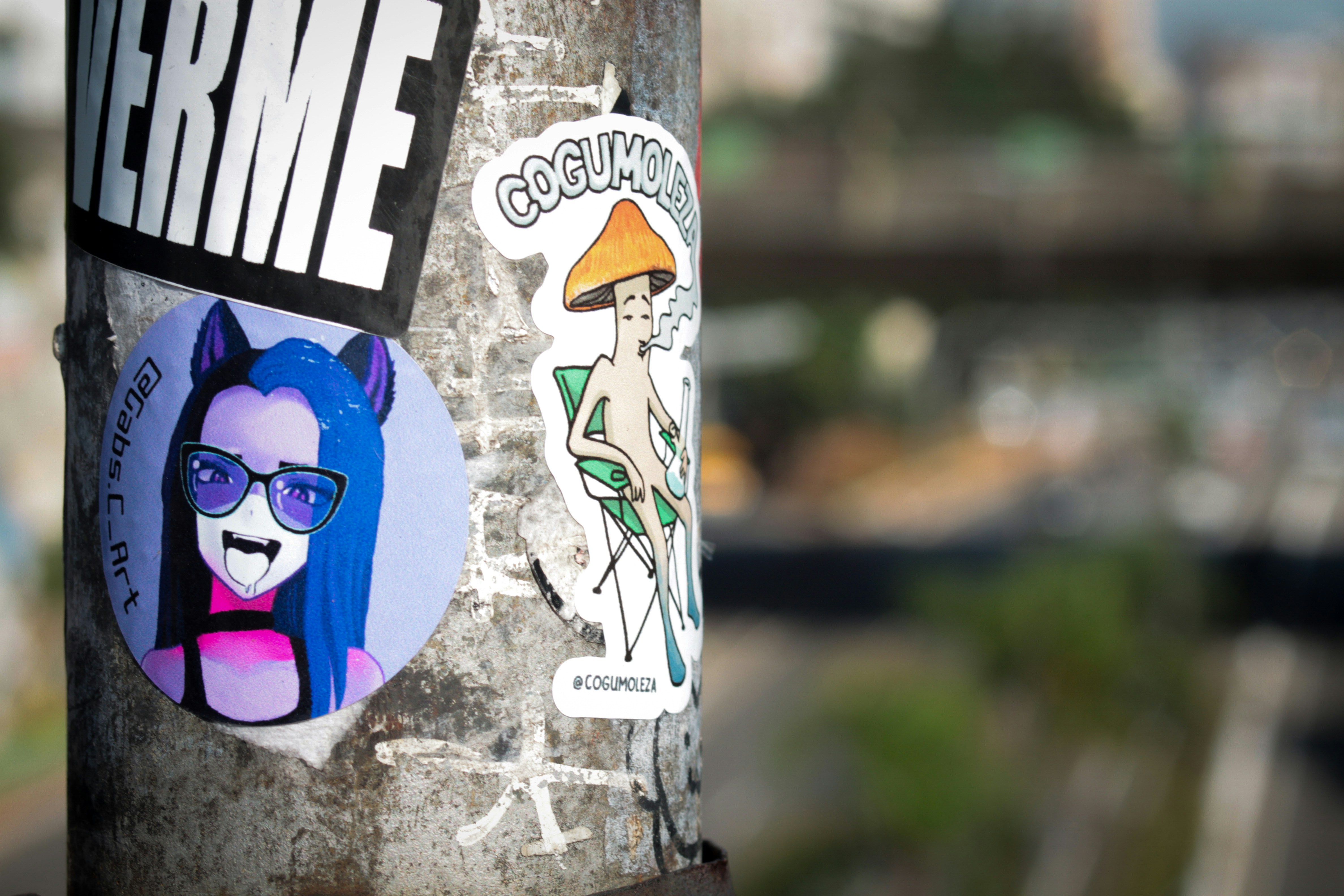 Sticker Portrait on Weathered Post: Neon Cat and Mushroom Artist Duo
