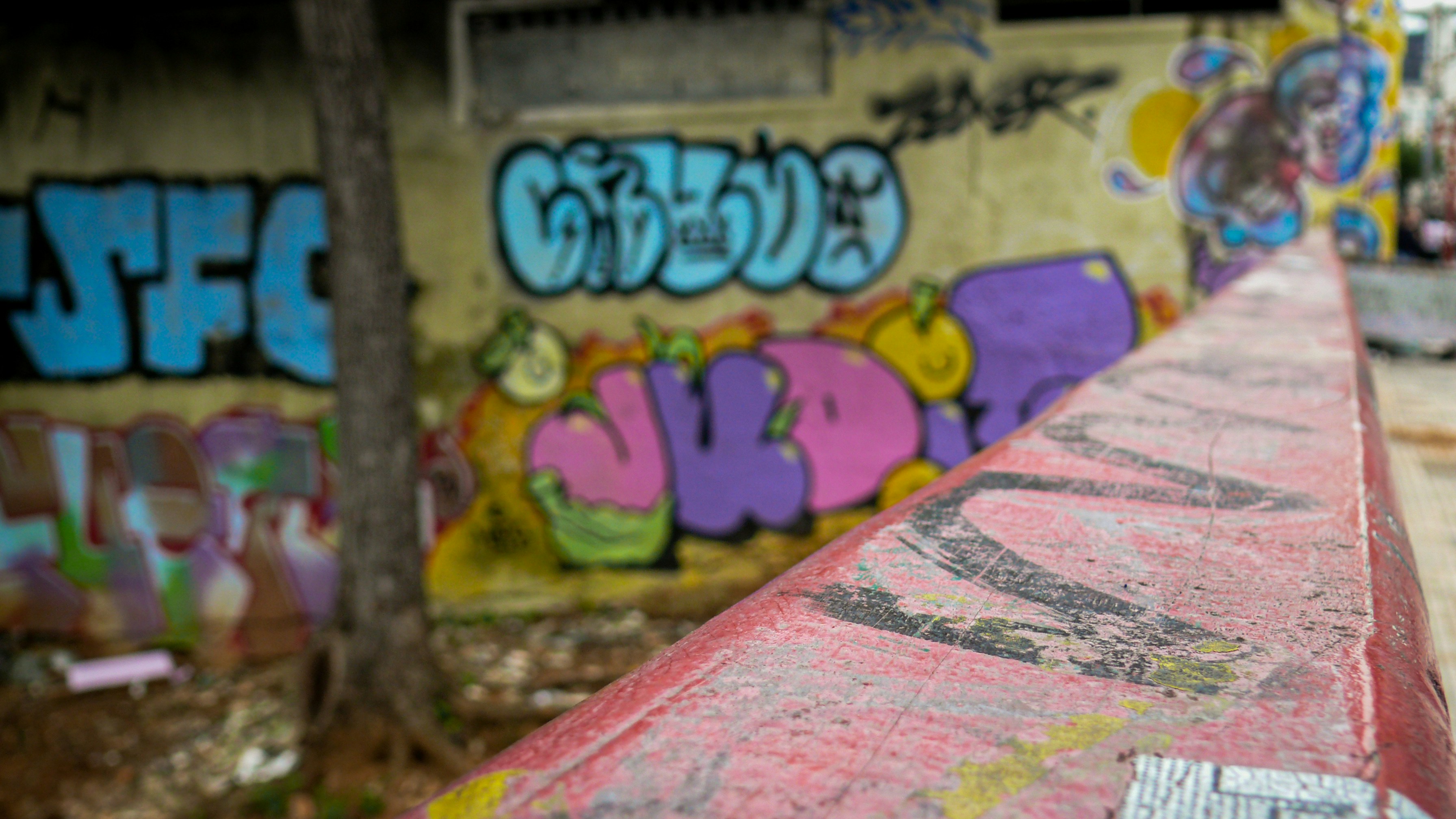 Colorful graffiti covers a wall behind a red concrete barrier.
