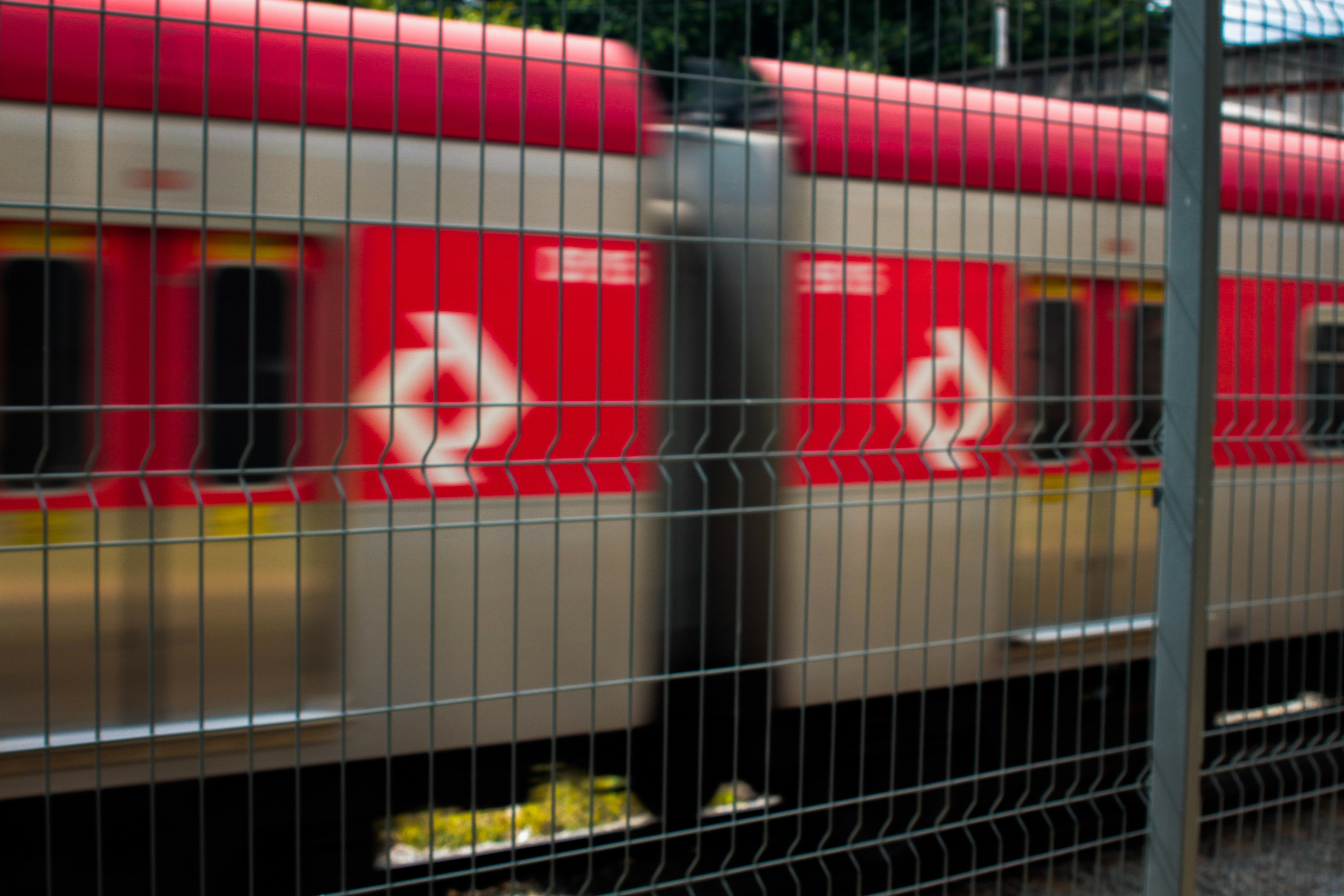 Red commuter in motion behind a safety fence
