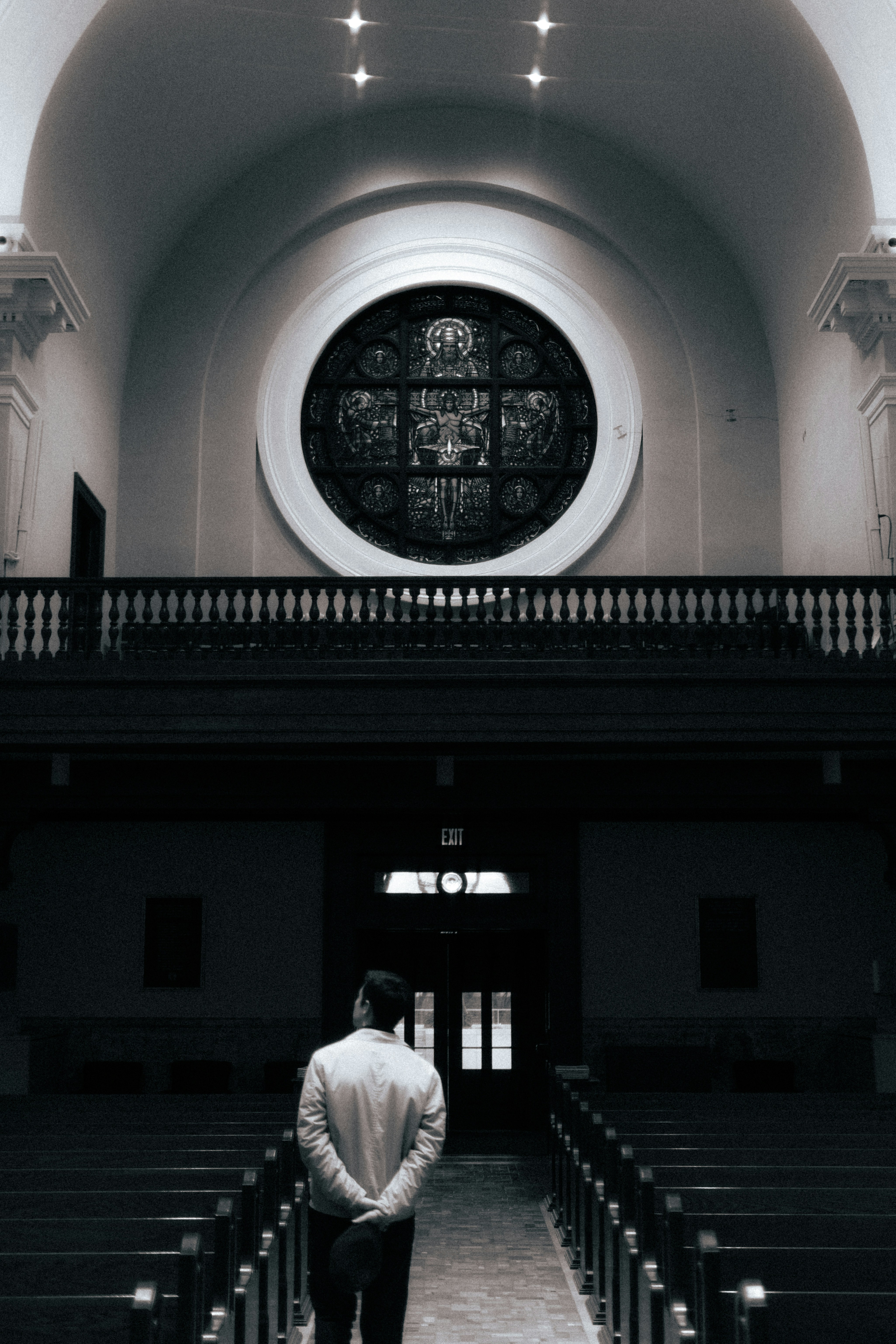 Silhouette in the Dome: A solitary figure beneath the grand stained-glass circular window