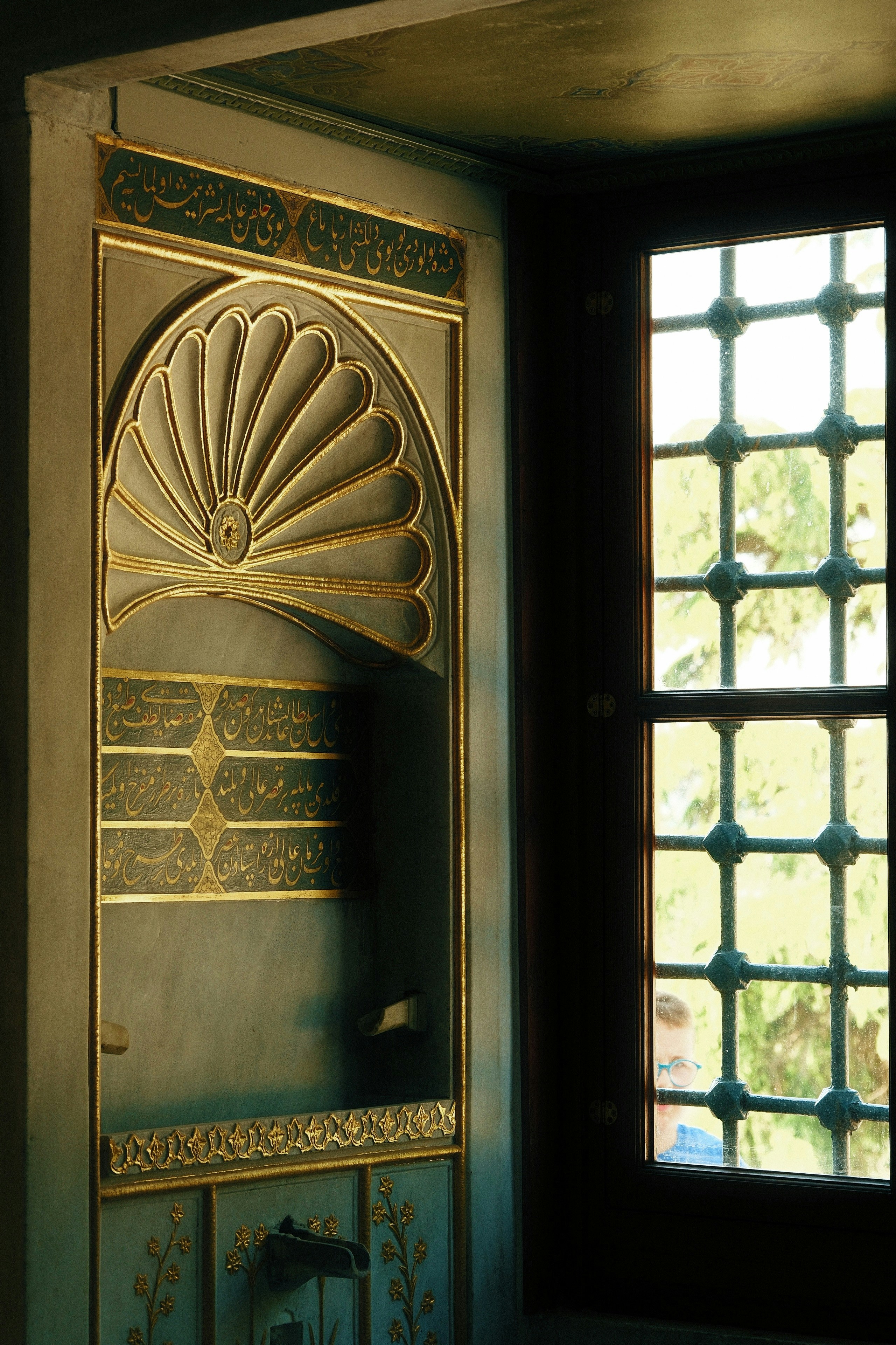 Ornate wall niche with calligraphy next to a window.