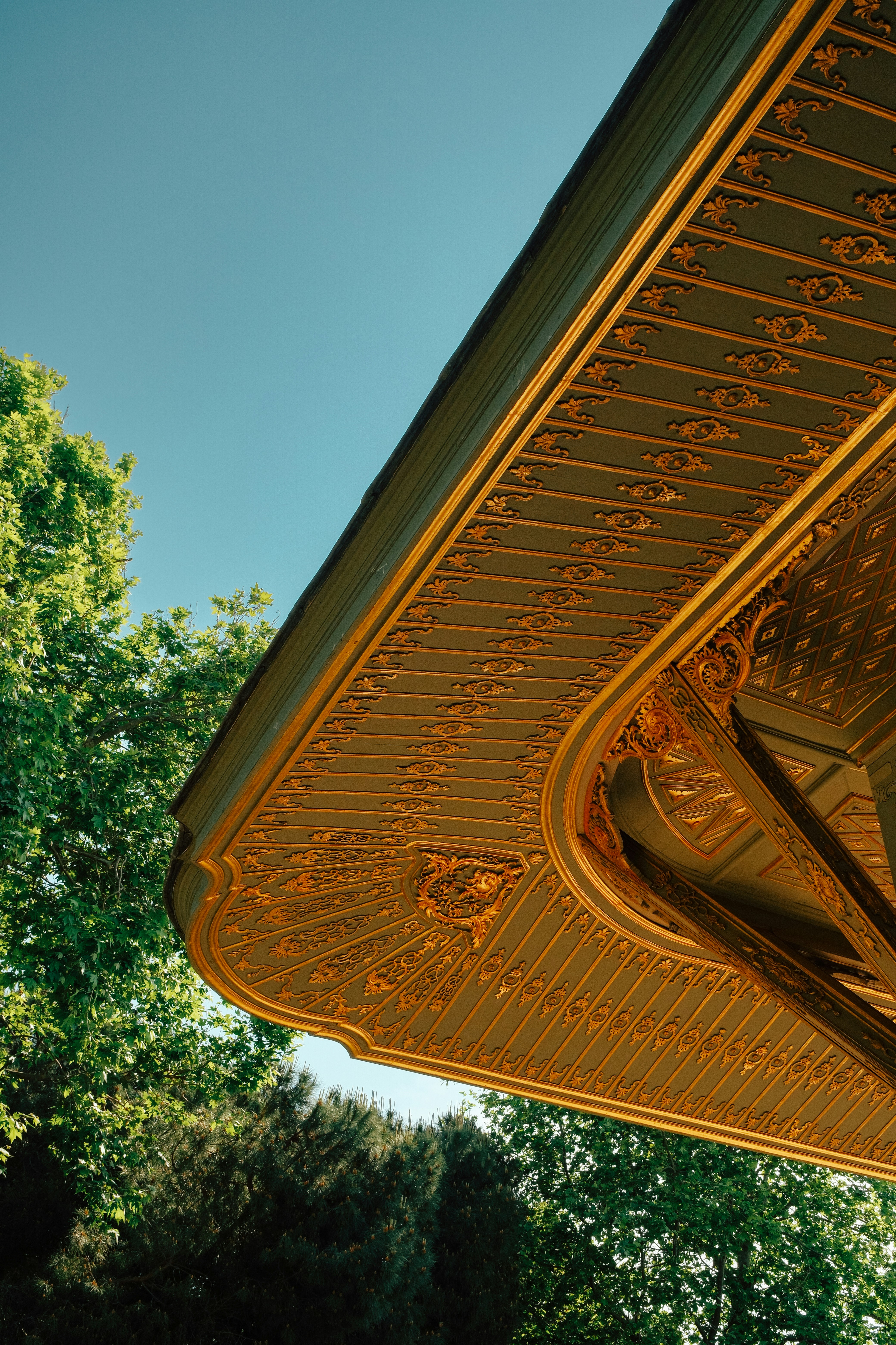 Ornate eave overhang: gilded detailing framing a sunlit canopy