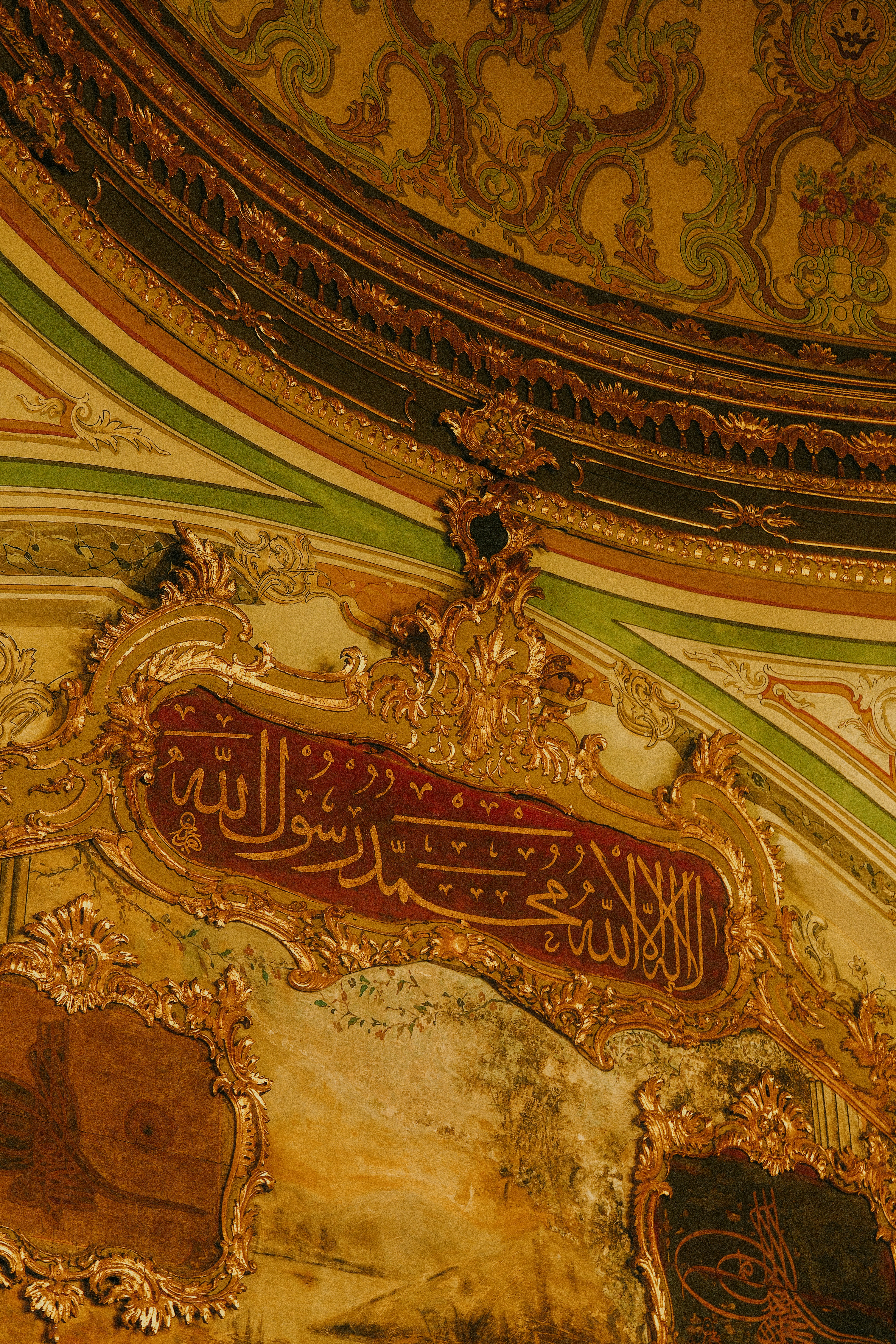 Ornate gold and red calligraphy on a decorative ceiling.