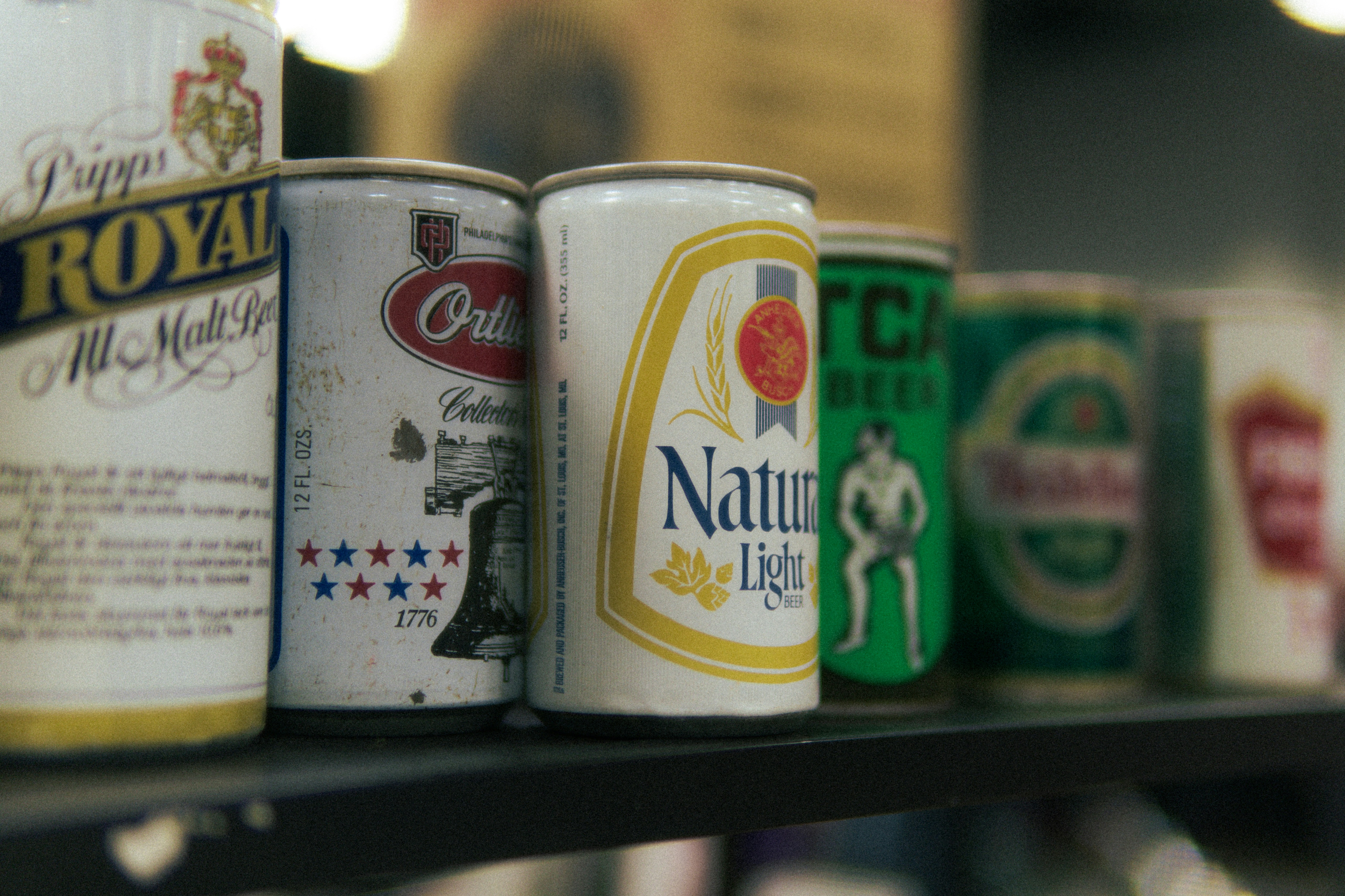 Amber-lit Shelf: A Row of Beer Cans in Focus