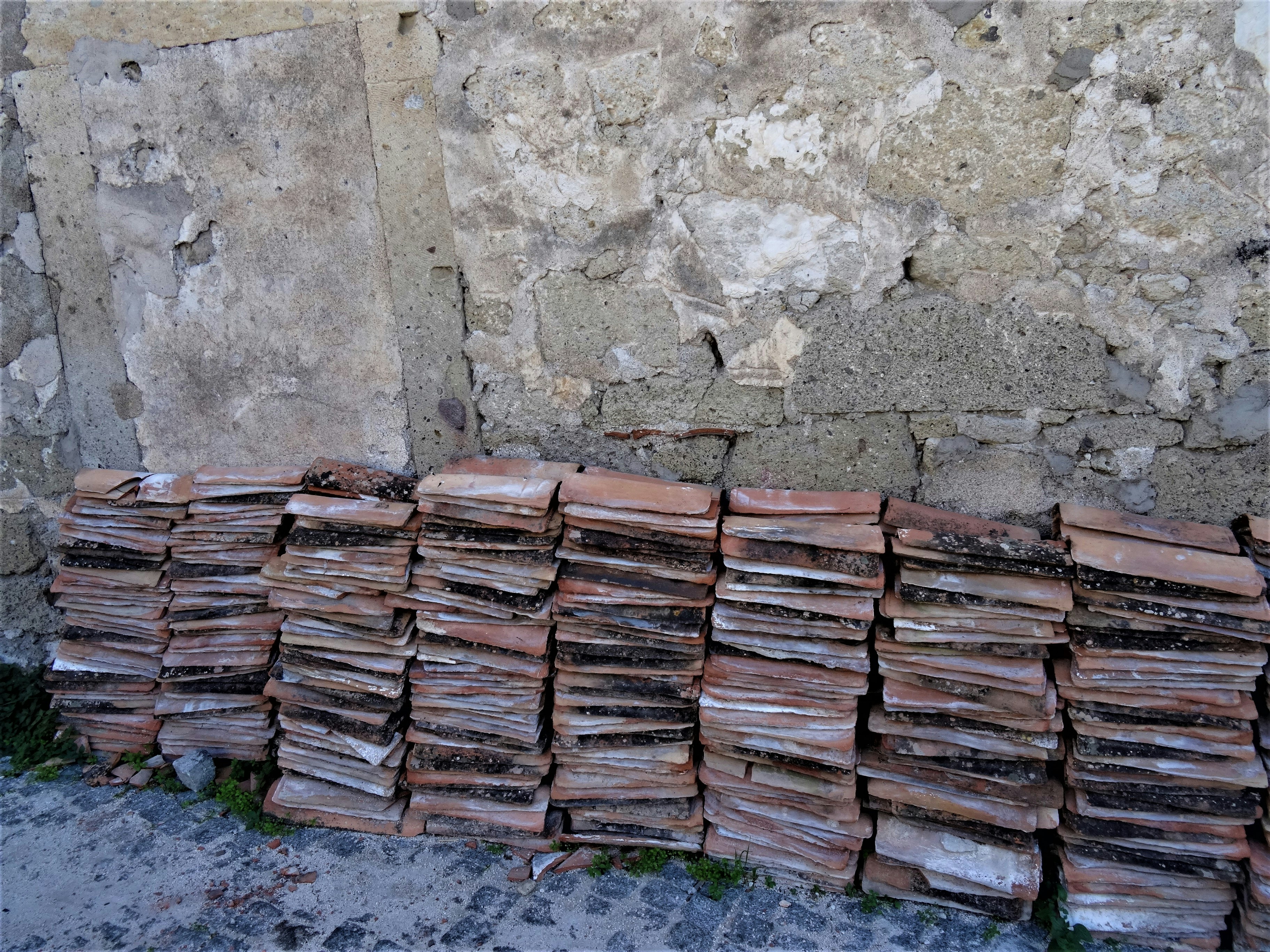 Stacked clay tiles against a weathered stone wall
