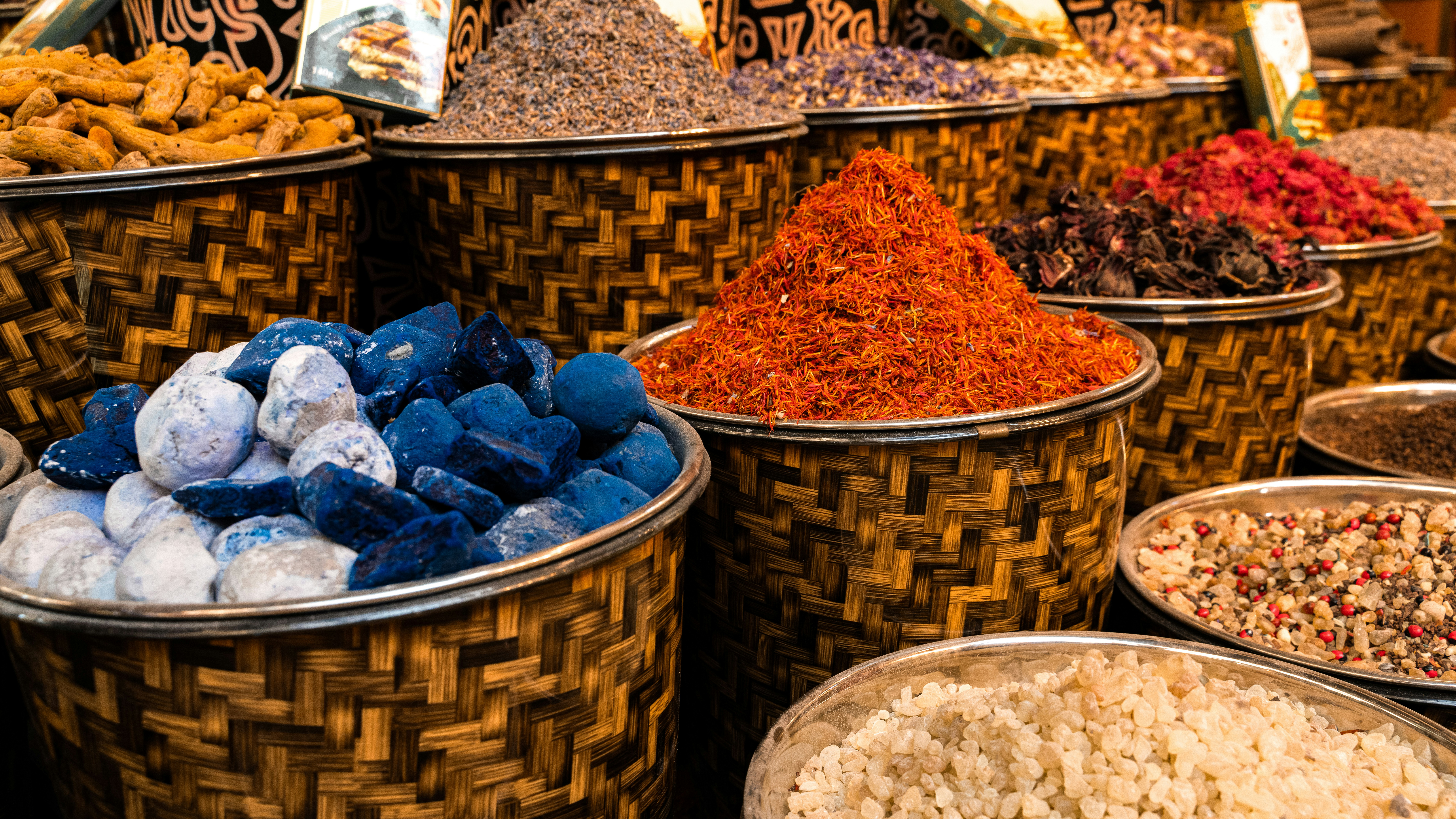 Vibrant spices and dried goods in woven market baskets.