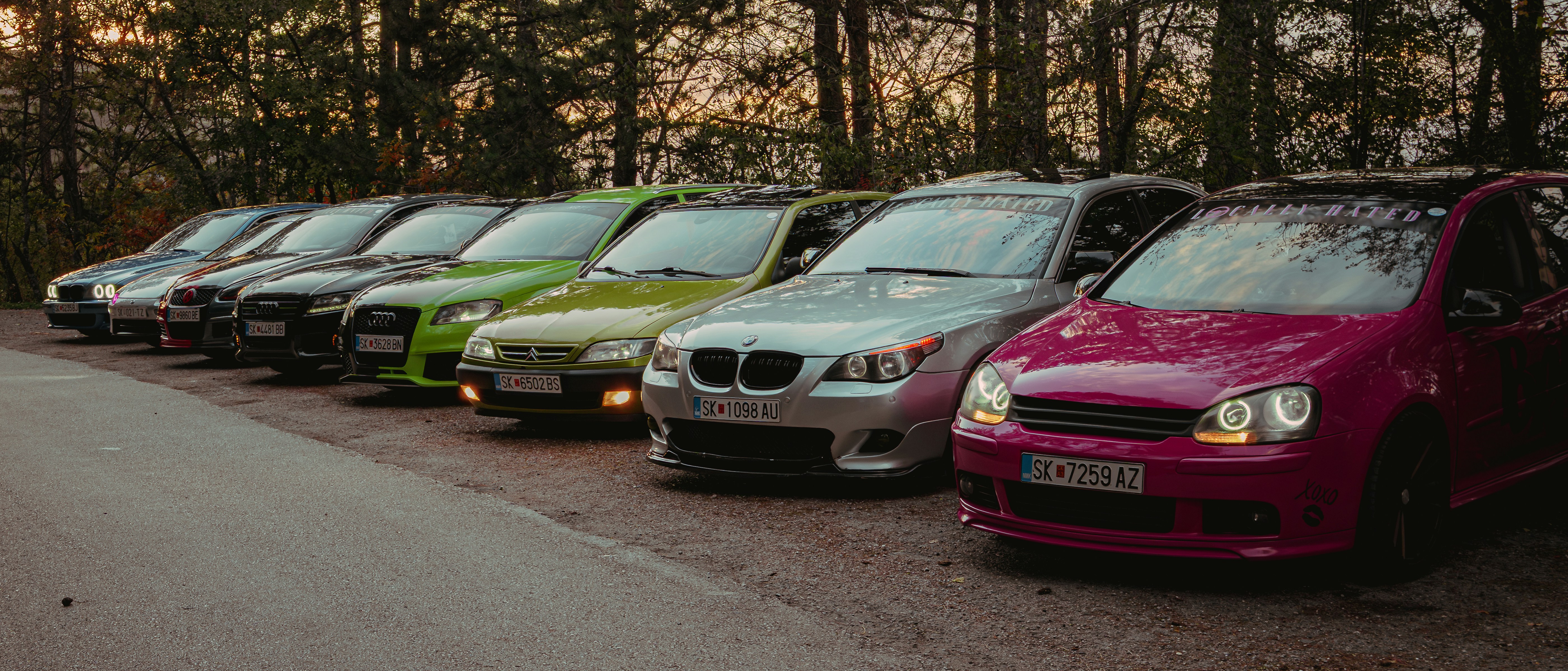 Vibrant lineup: a row of colorful compact cars in a gravel lot