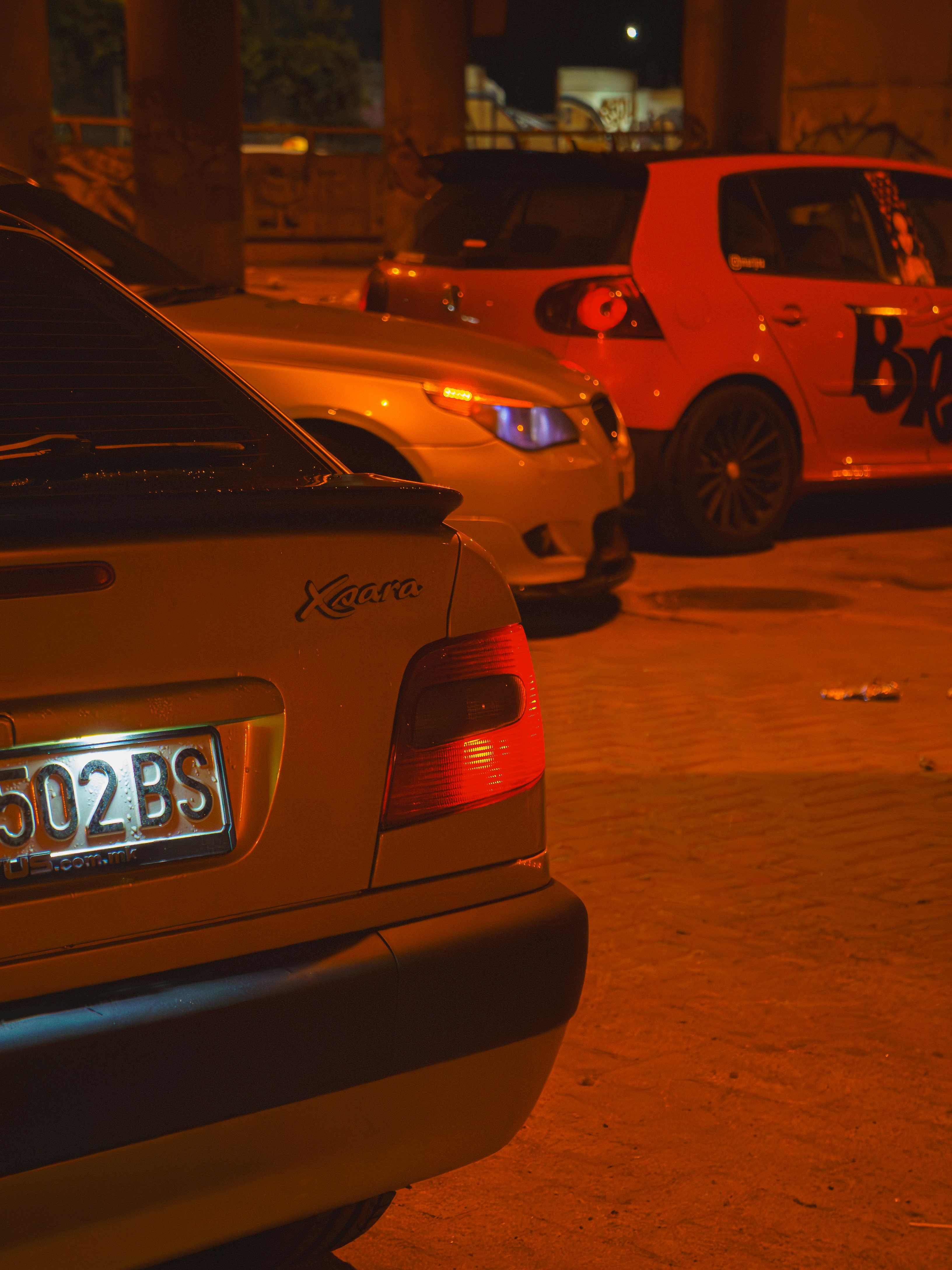 Low-slung Beetle under Orange Night: Street Scene with Parked Cars