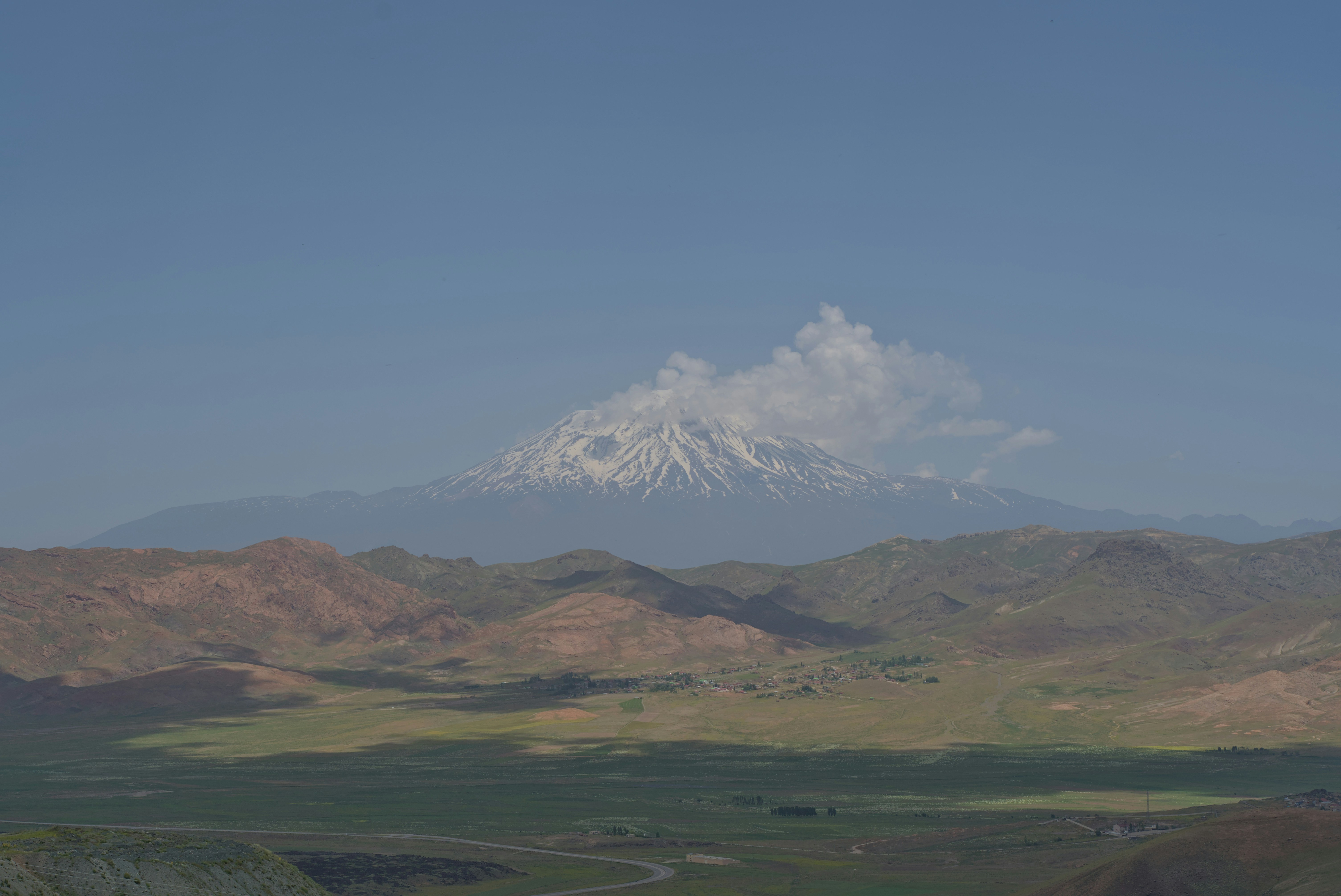 Snowcapped Peak Over Rolling Desert Hills