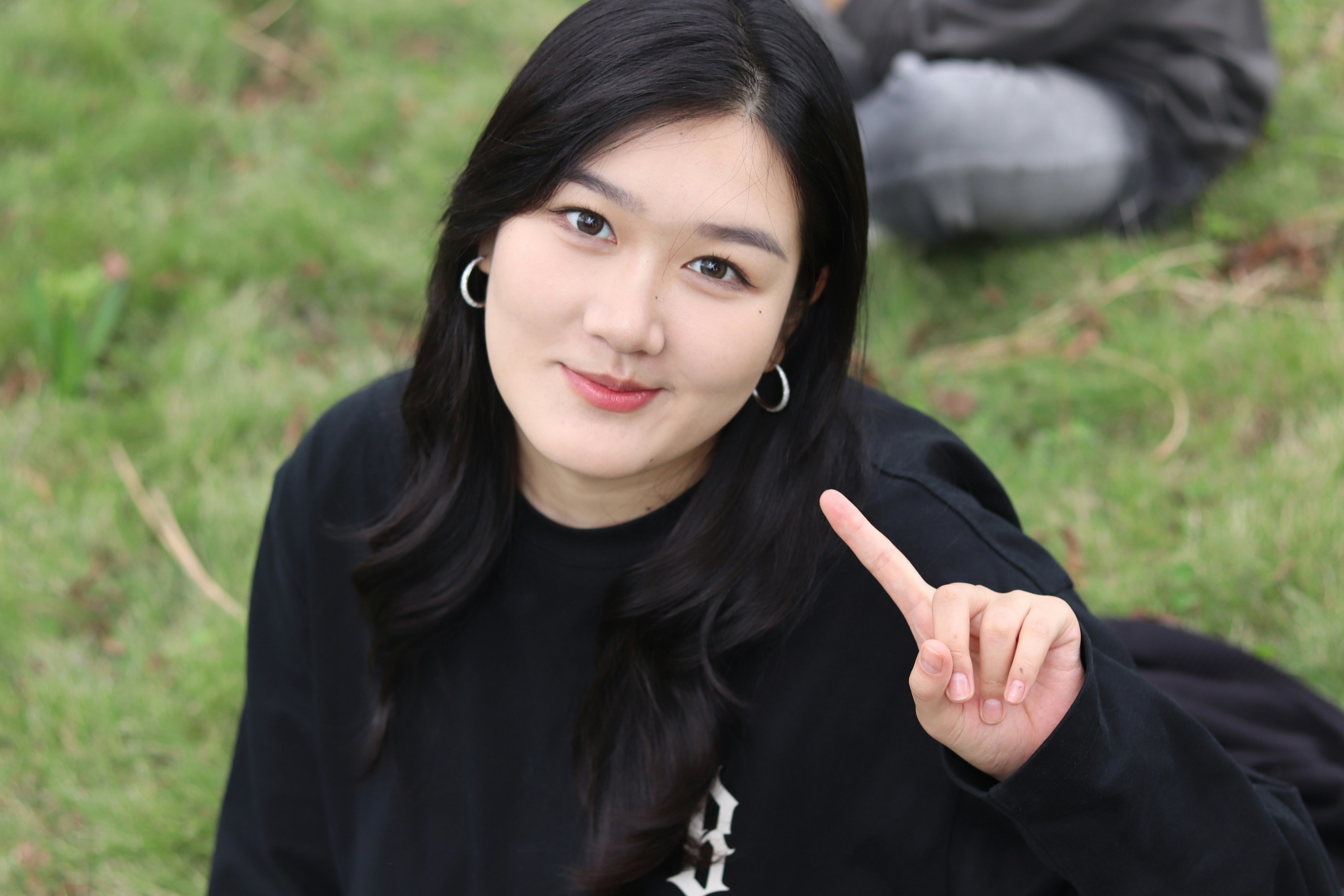 Portrait in Grass: A Soft Smile and a Pointed Gesture