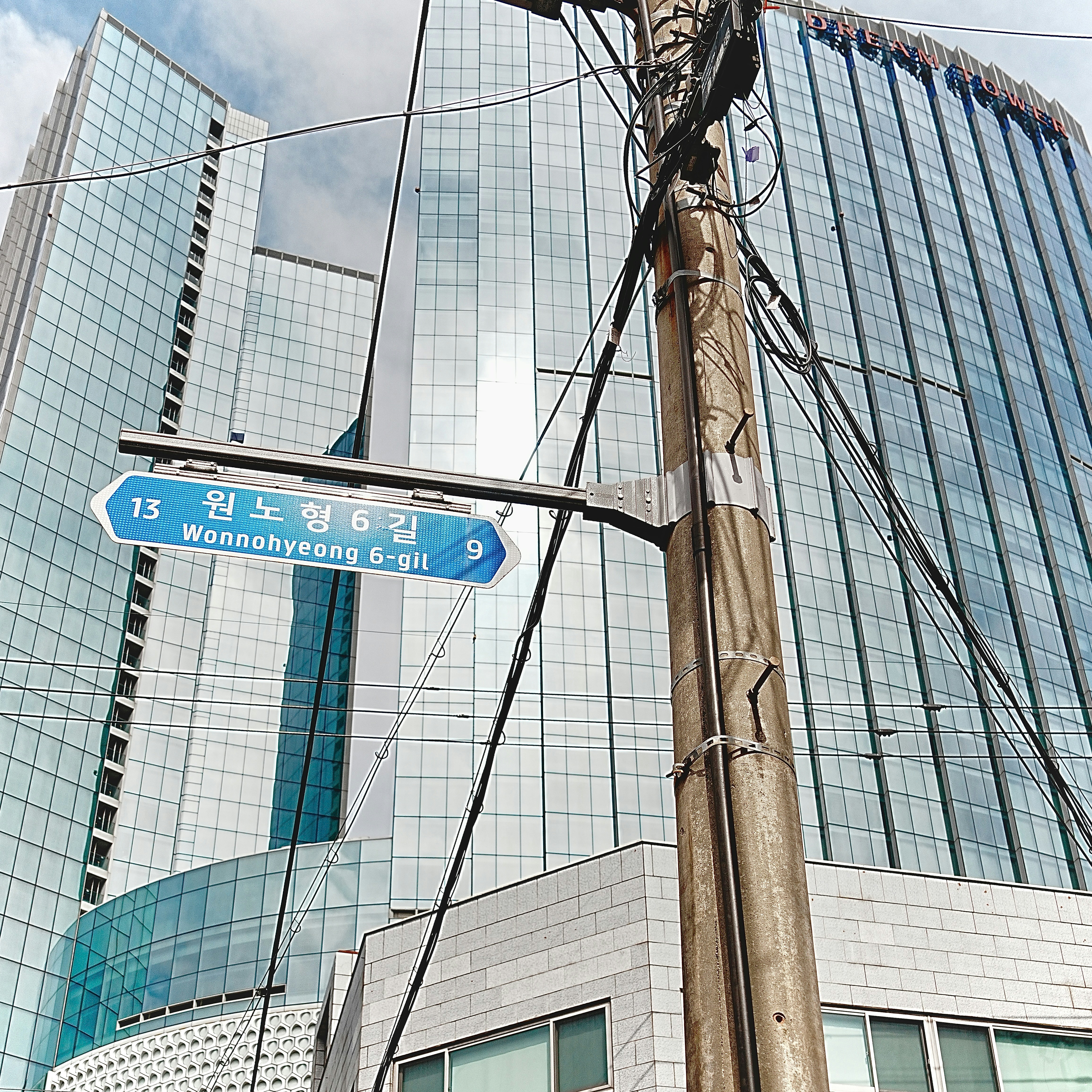Urban Glass and Wires: A Street Sign Under Skyscrapers