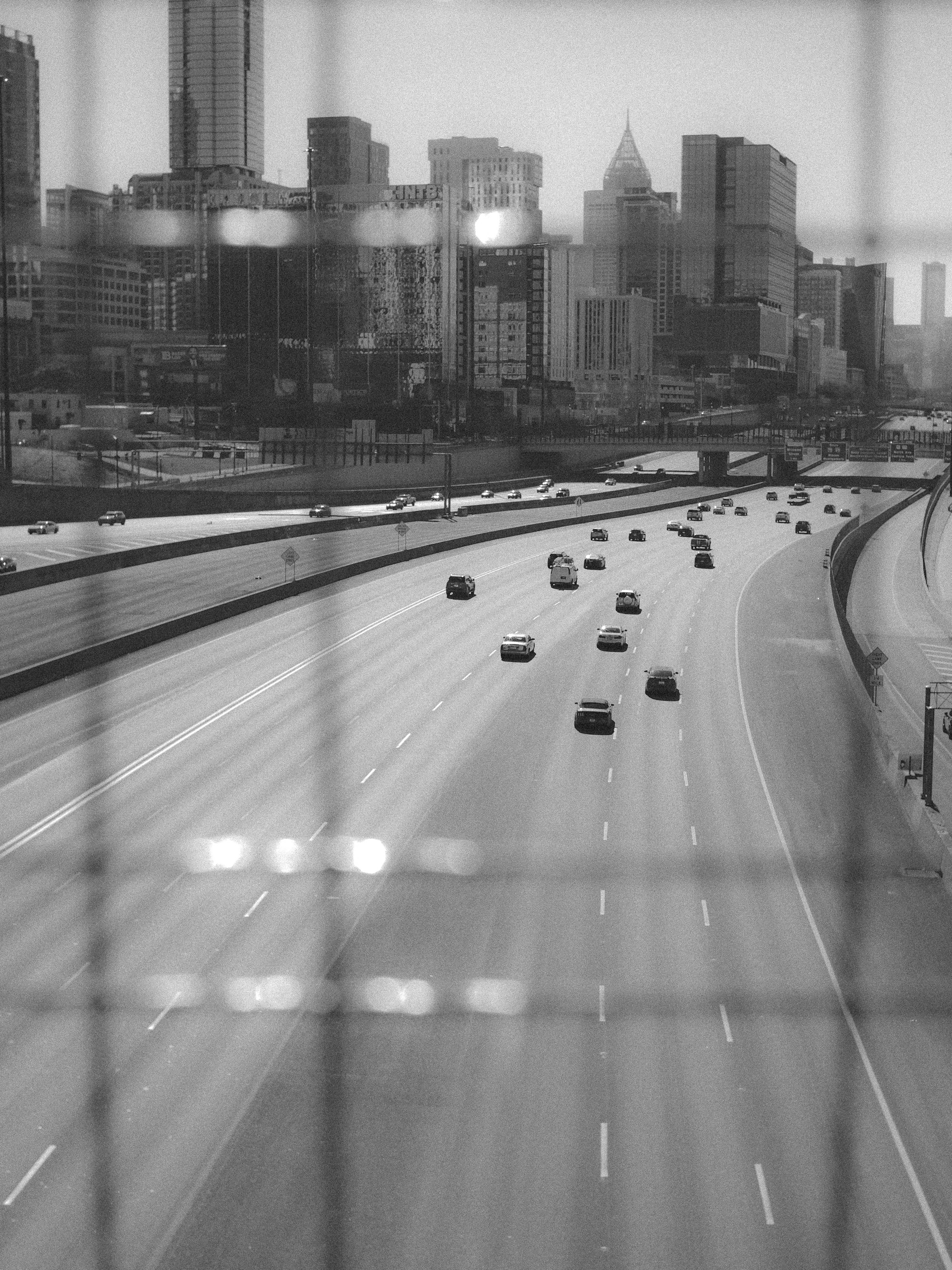Black and white highway with cars and city skyline.