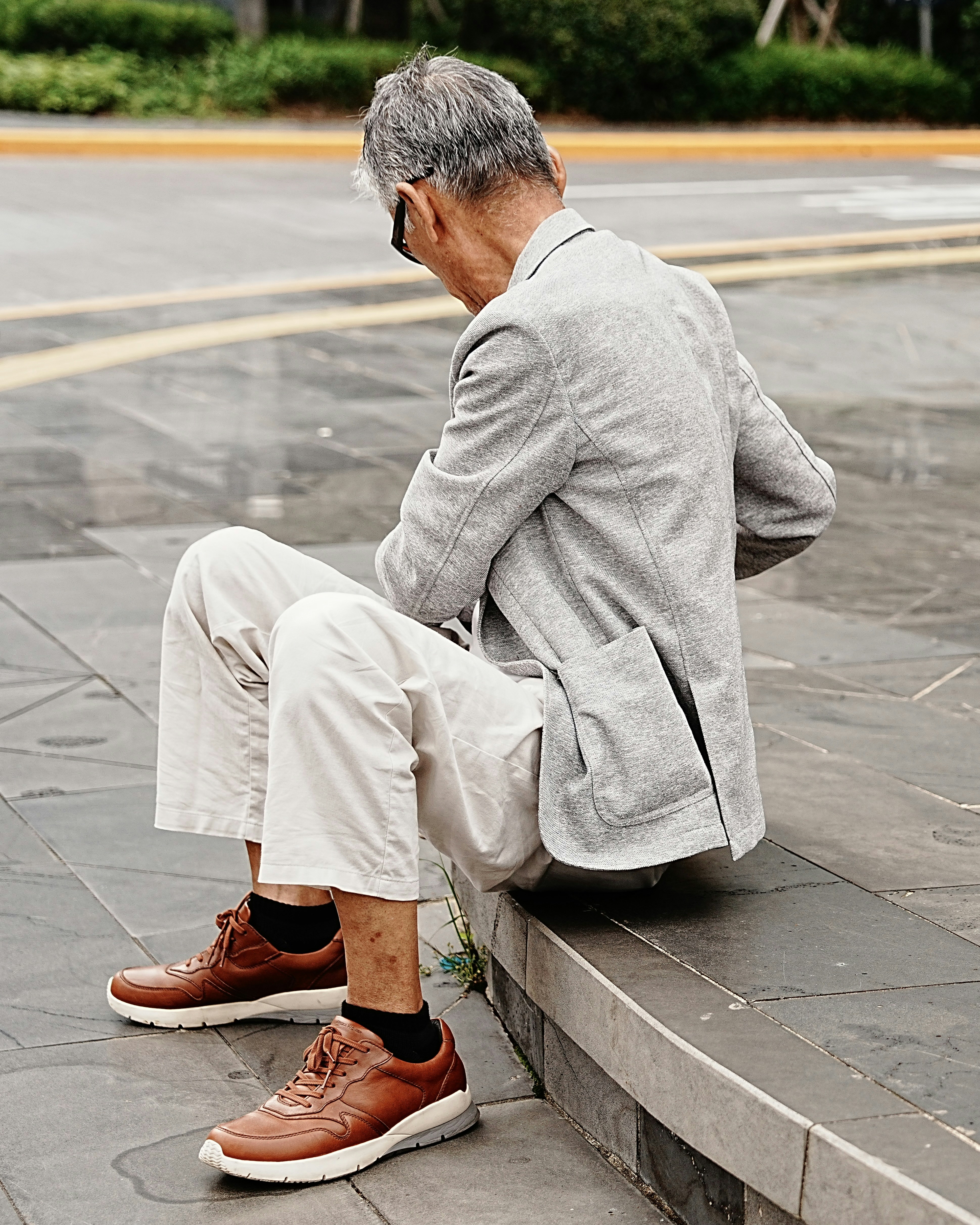 Quiet pause at the plaza: a gray-suited man adjusting a sleeve