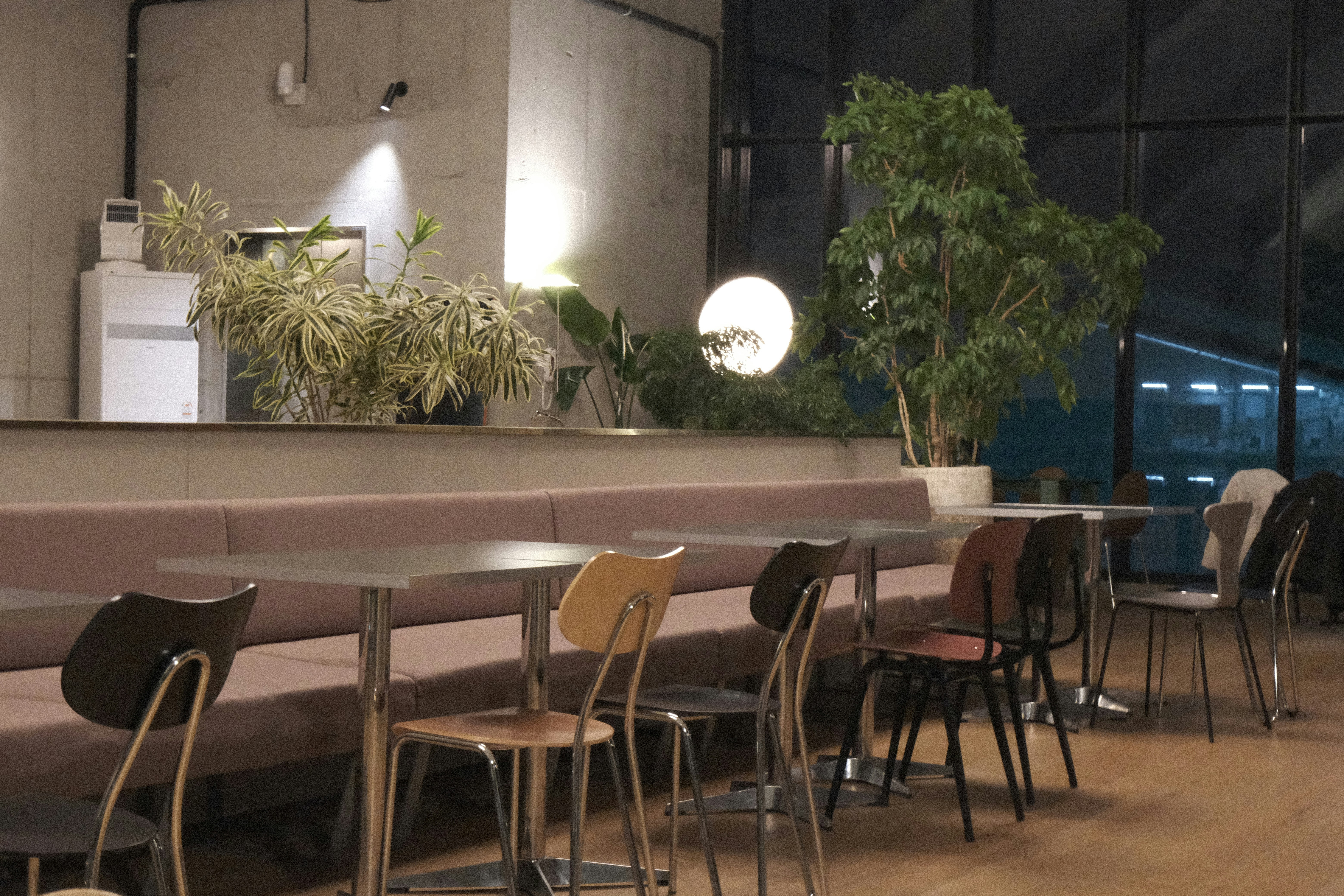 Empty modern cafe interior with tables, chairs, and plants.