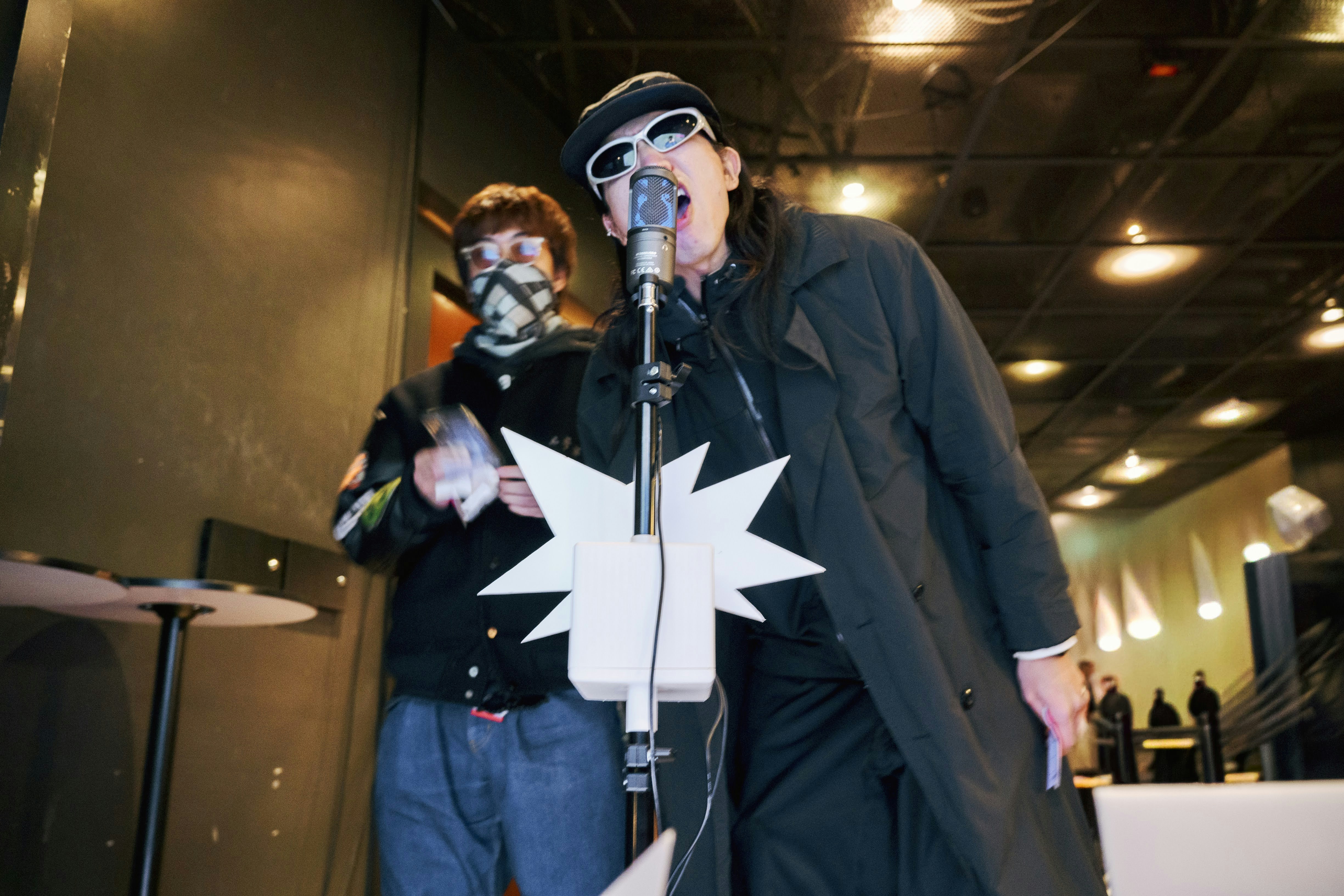 A person sings passionately into a star-decorated microphone.