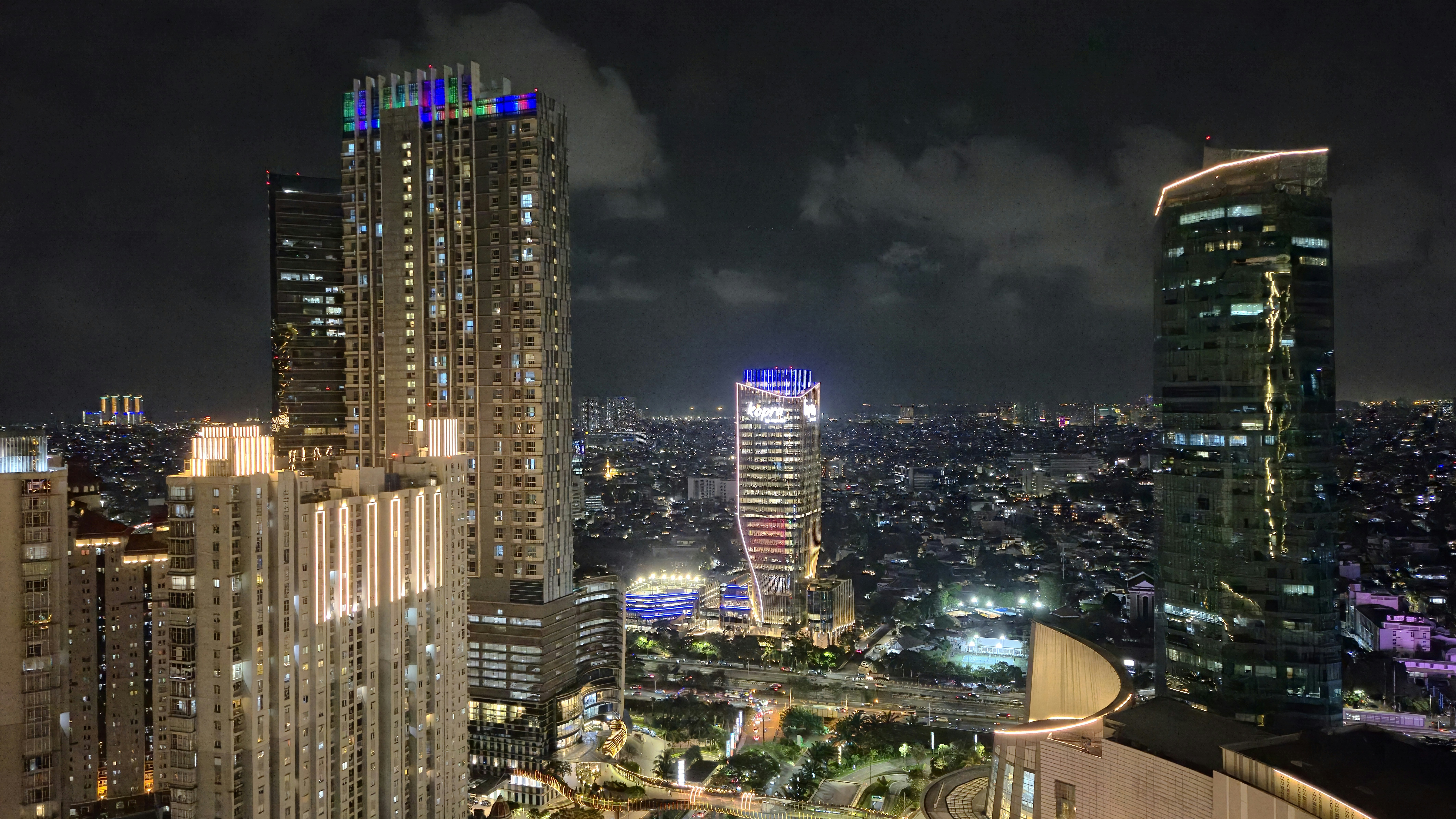 Nightfall Skyline: City Lights Flow Over a Crown of Towers
