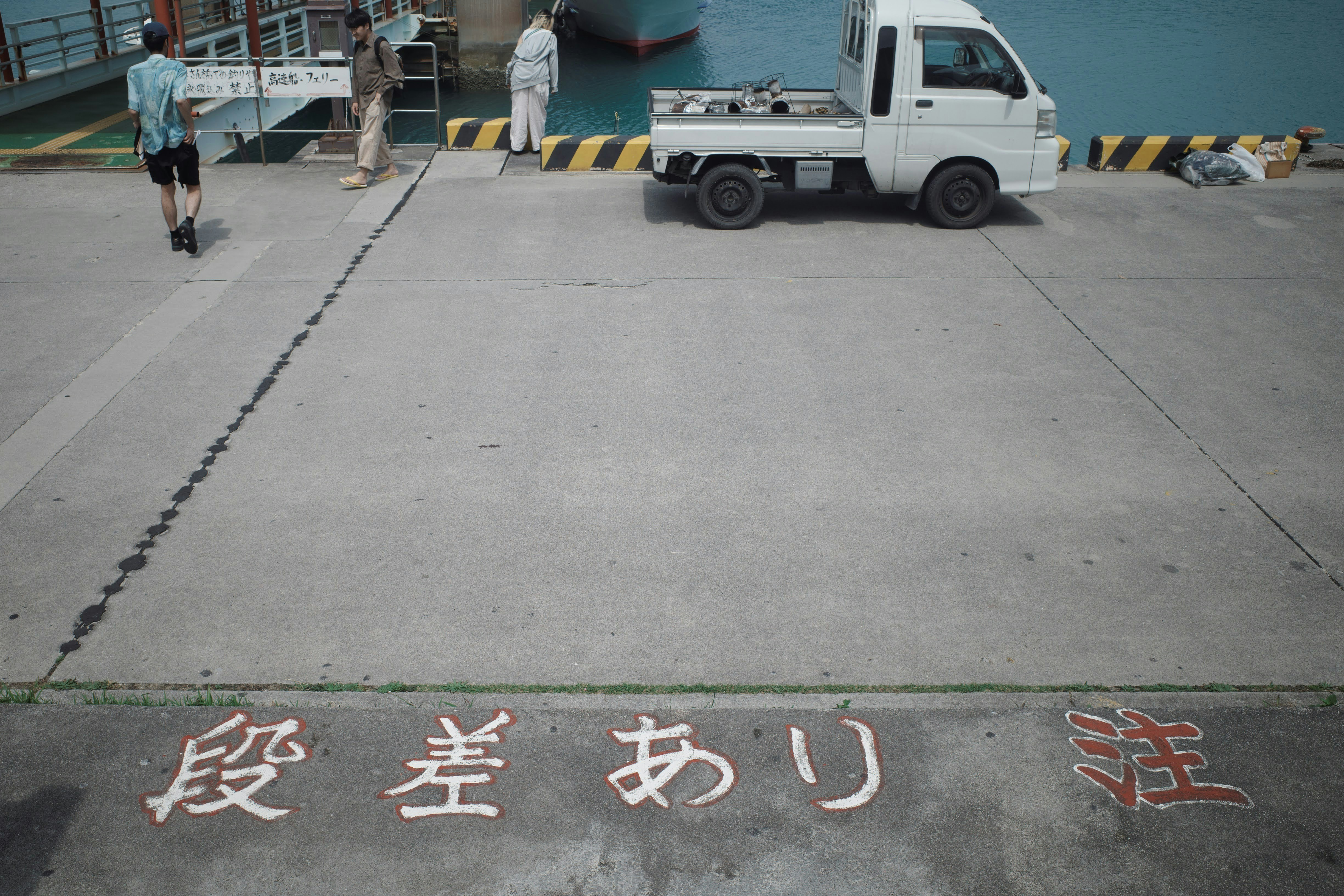 Harborfront in Quiet Motion: People, Vehicle, and Painted Messages
