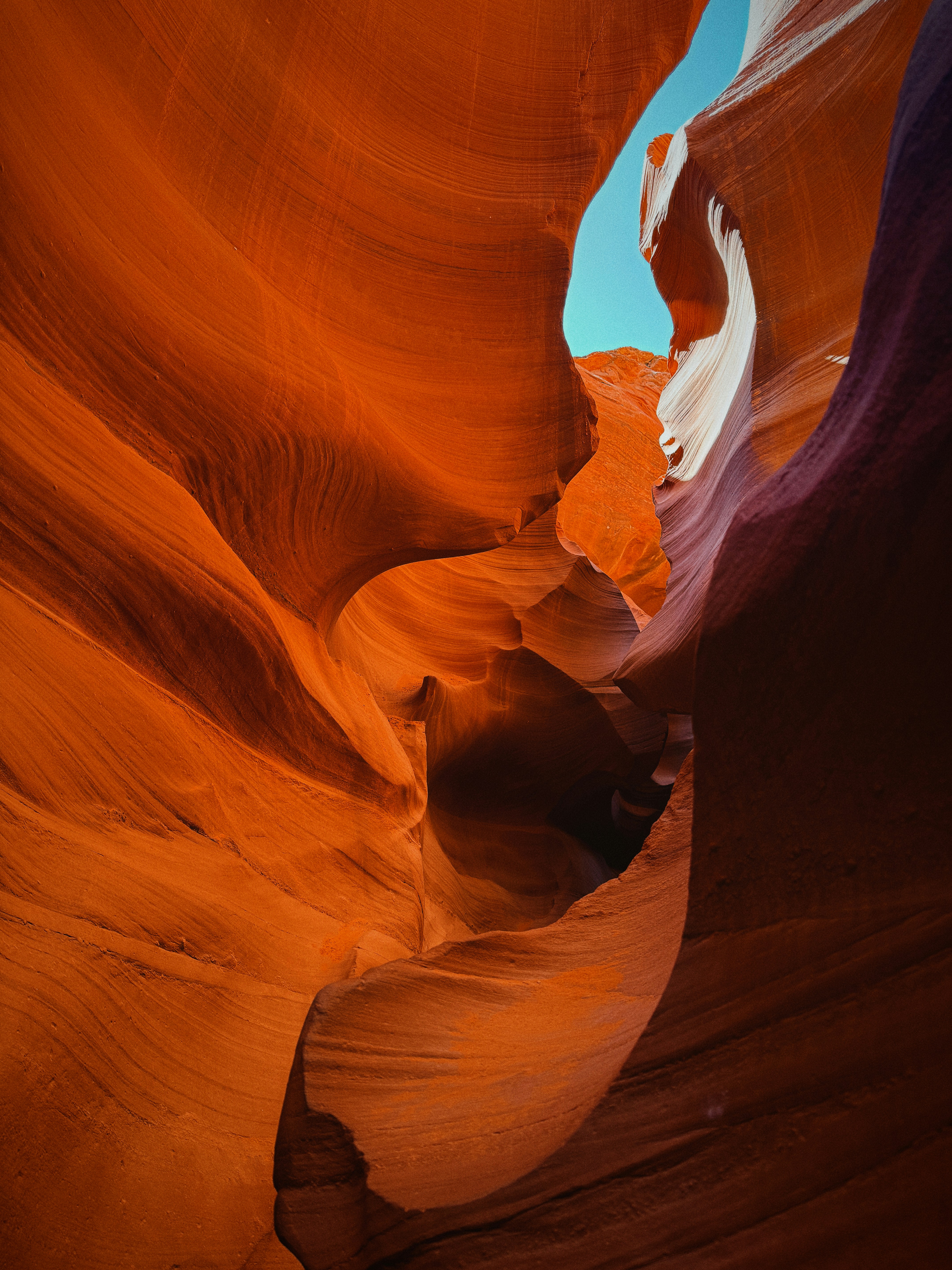 Dramatic orange slot canyon with a glimpse of blue sky.
