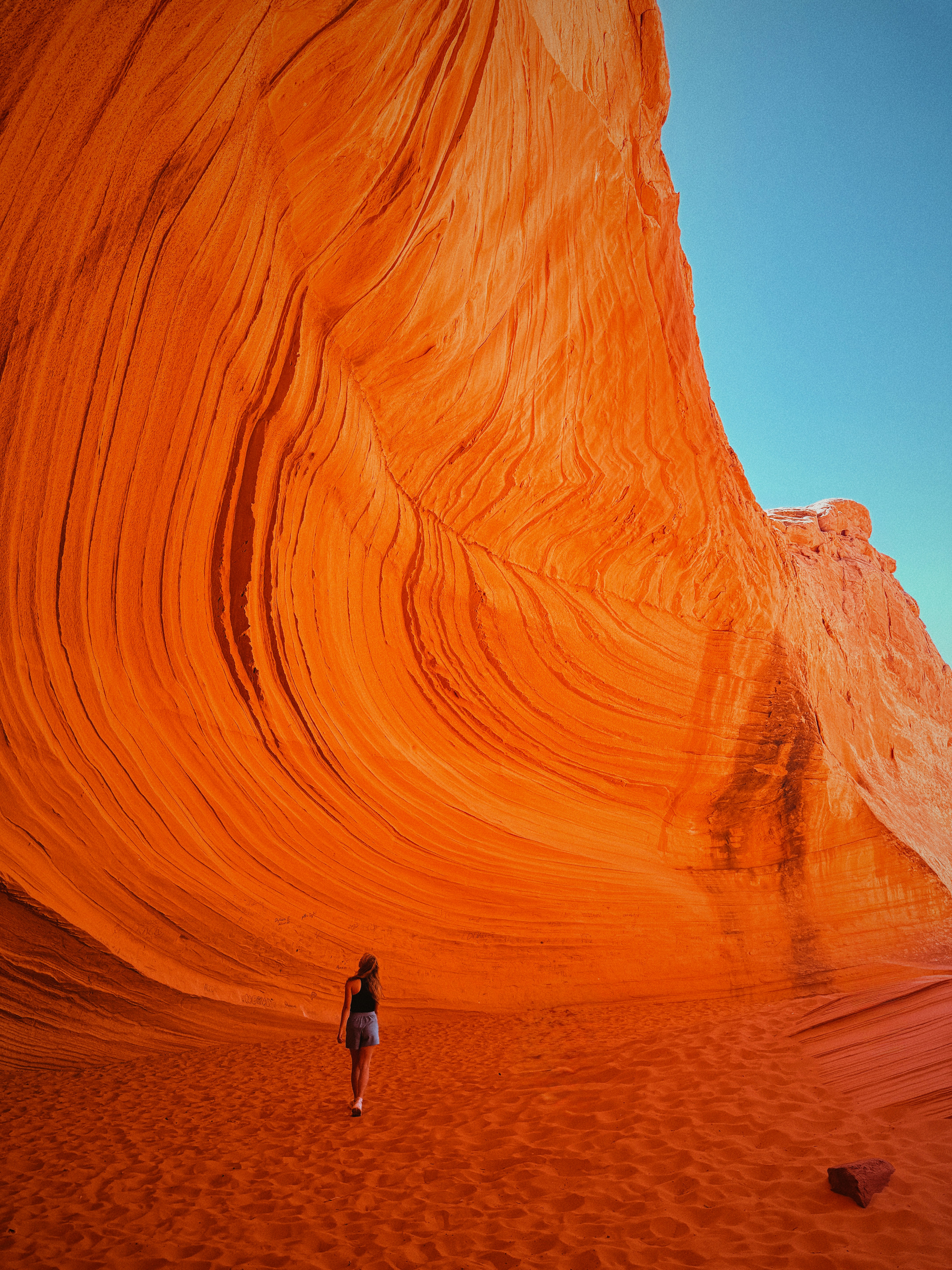 Desert Carved Face: A lone traveler under volcanic cliffs