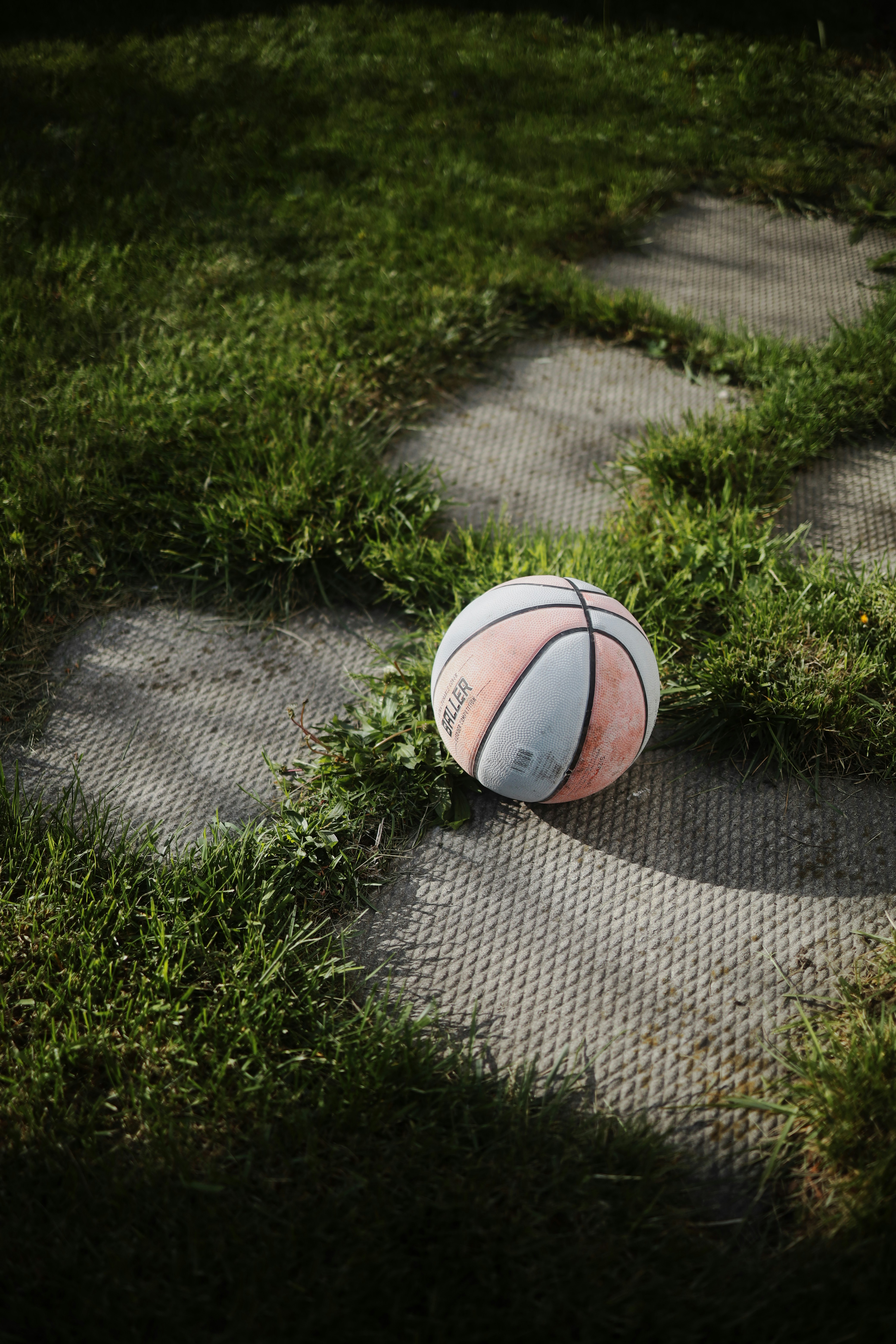 Weathered basketball resting on a sunlit garden path