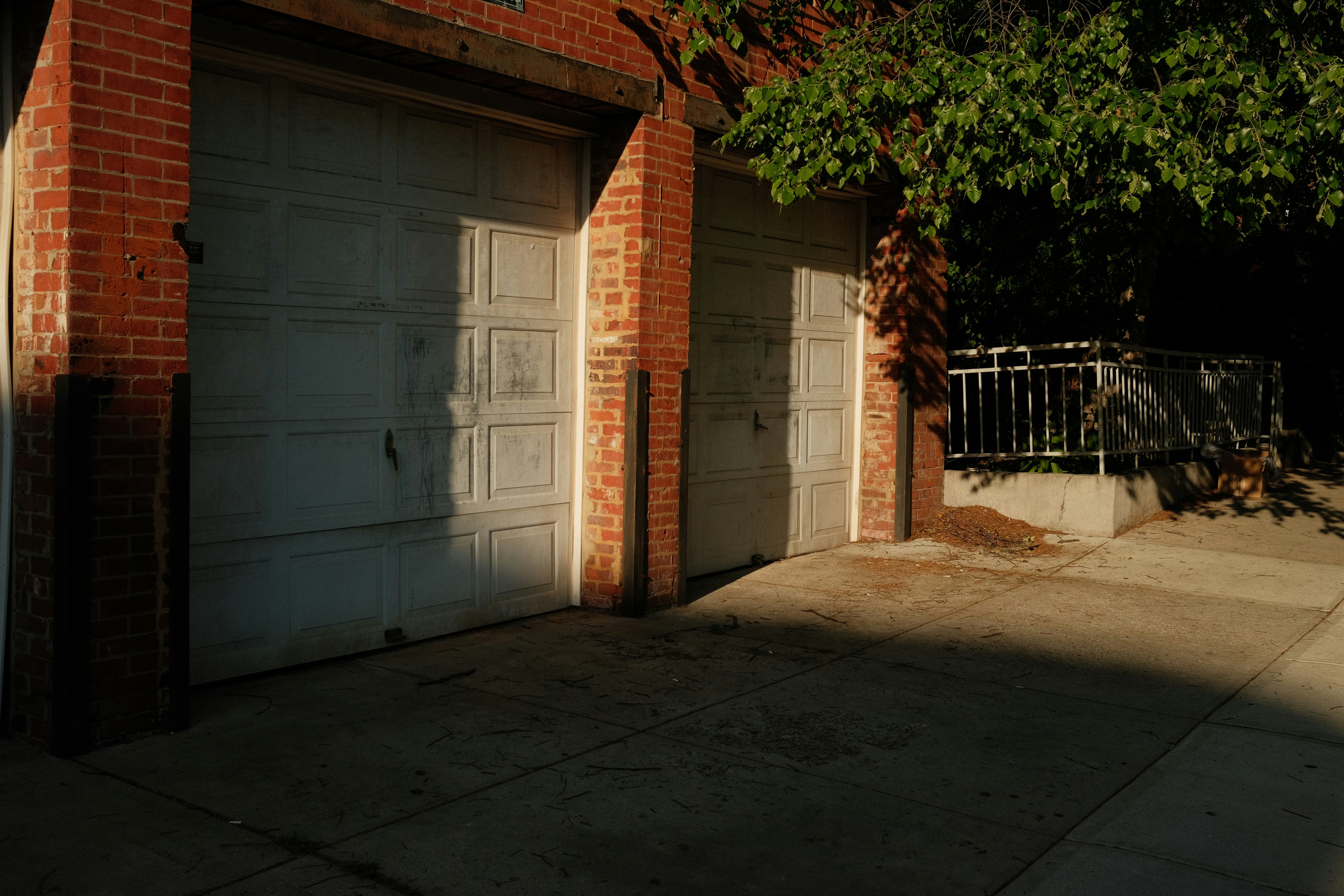 Sunlight casts shadows on two white garage doors.
