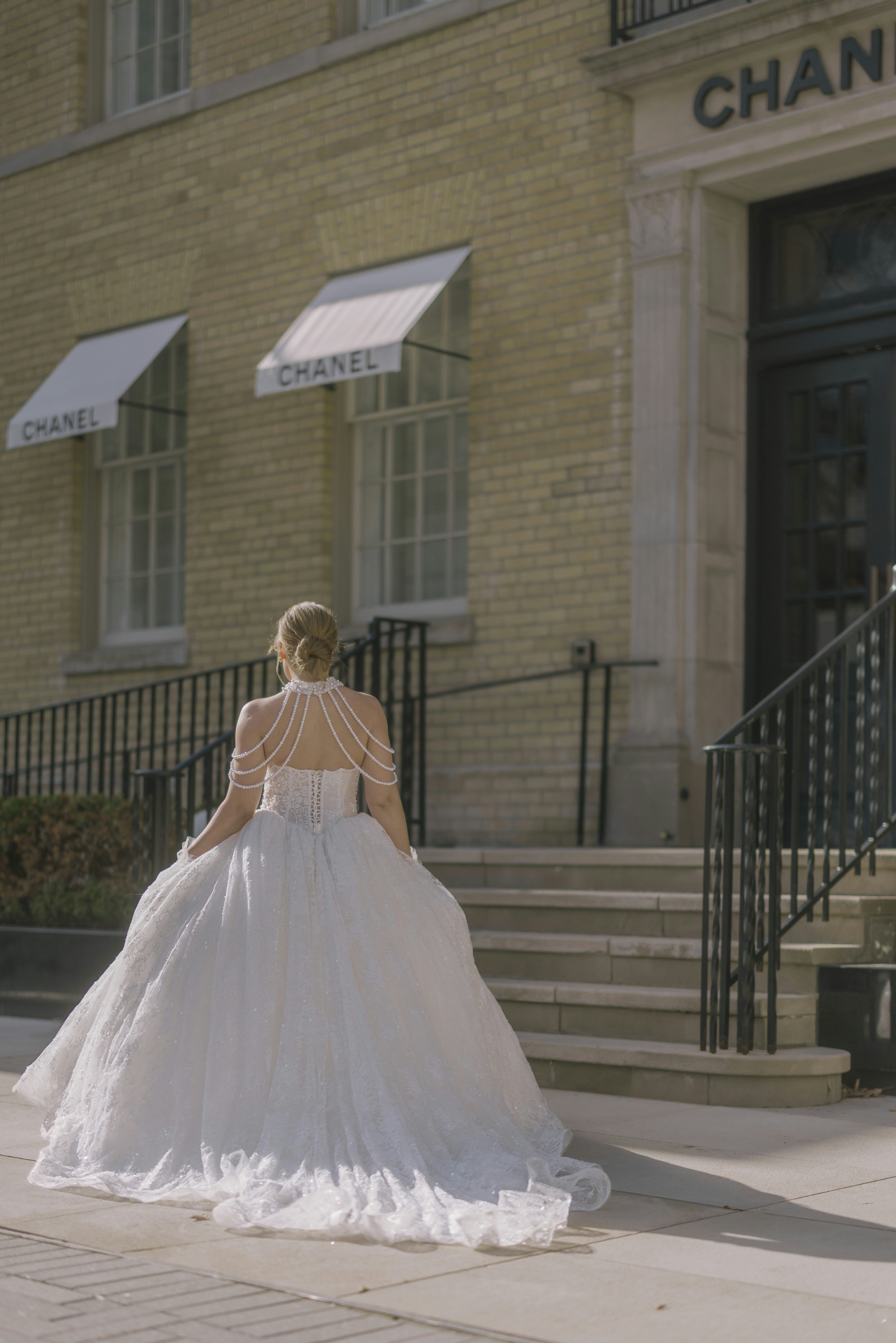 Bride in White Gown Ascends a City Staircase by Chanel Facade