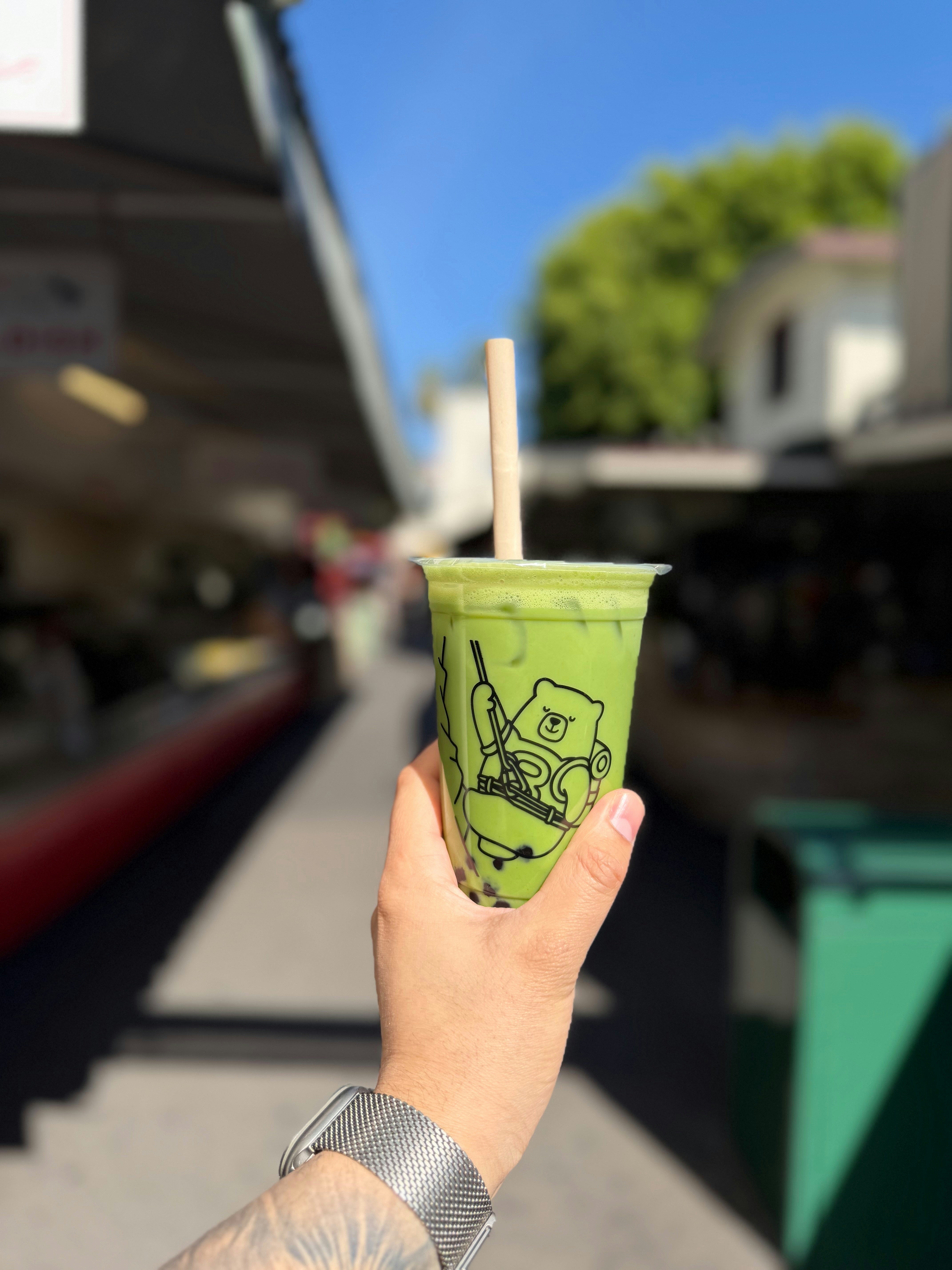 Green Milk Tea in a Handheld Cup with Cartoon Branding
