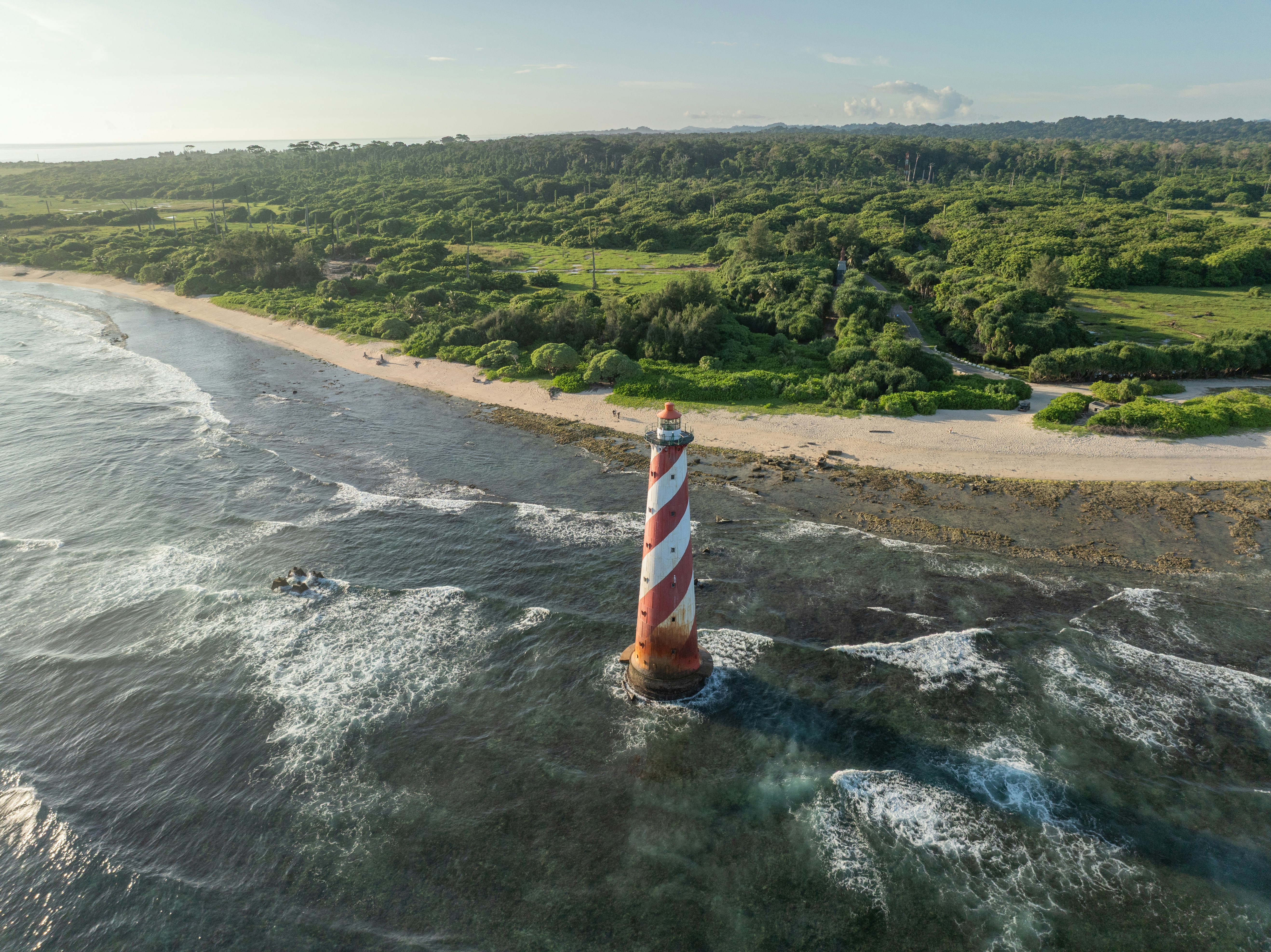 Lighthouse Sentinel: Aerial View of a Striped Beacon Standing Guard Over the Coastal Expanse