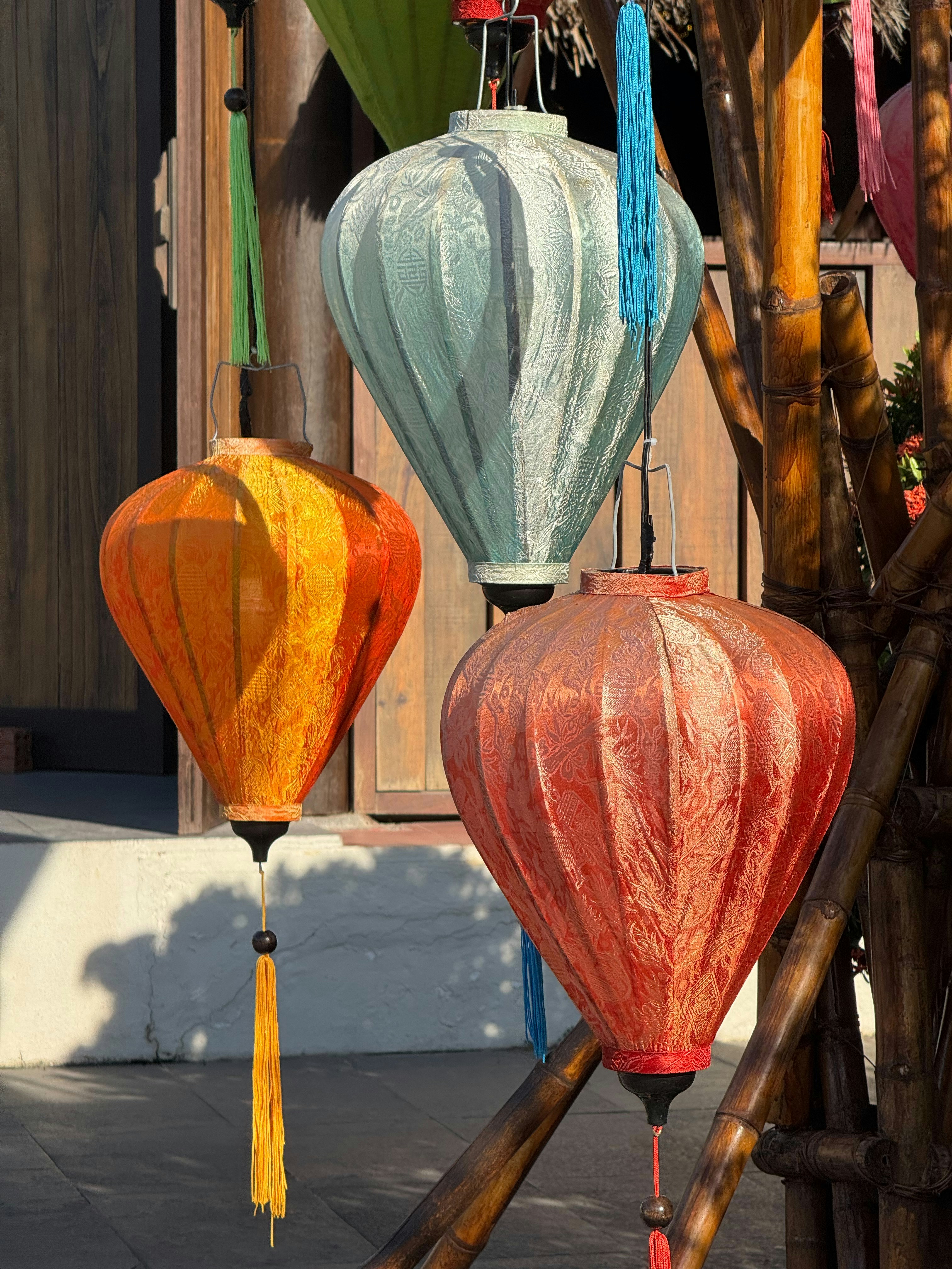 Midday Lantern Parade: A Trio of Paper Lanterns Against Wooden Stacks