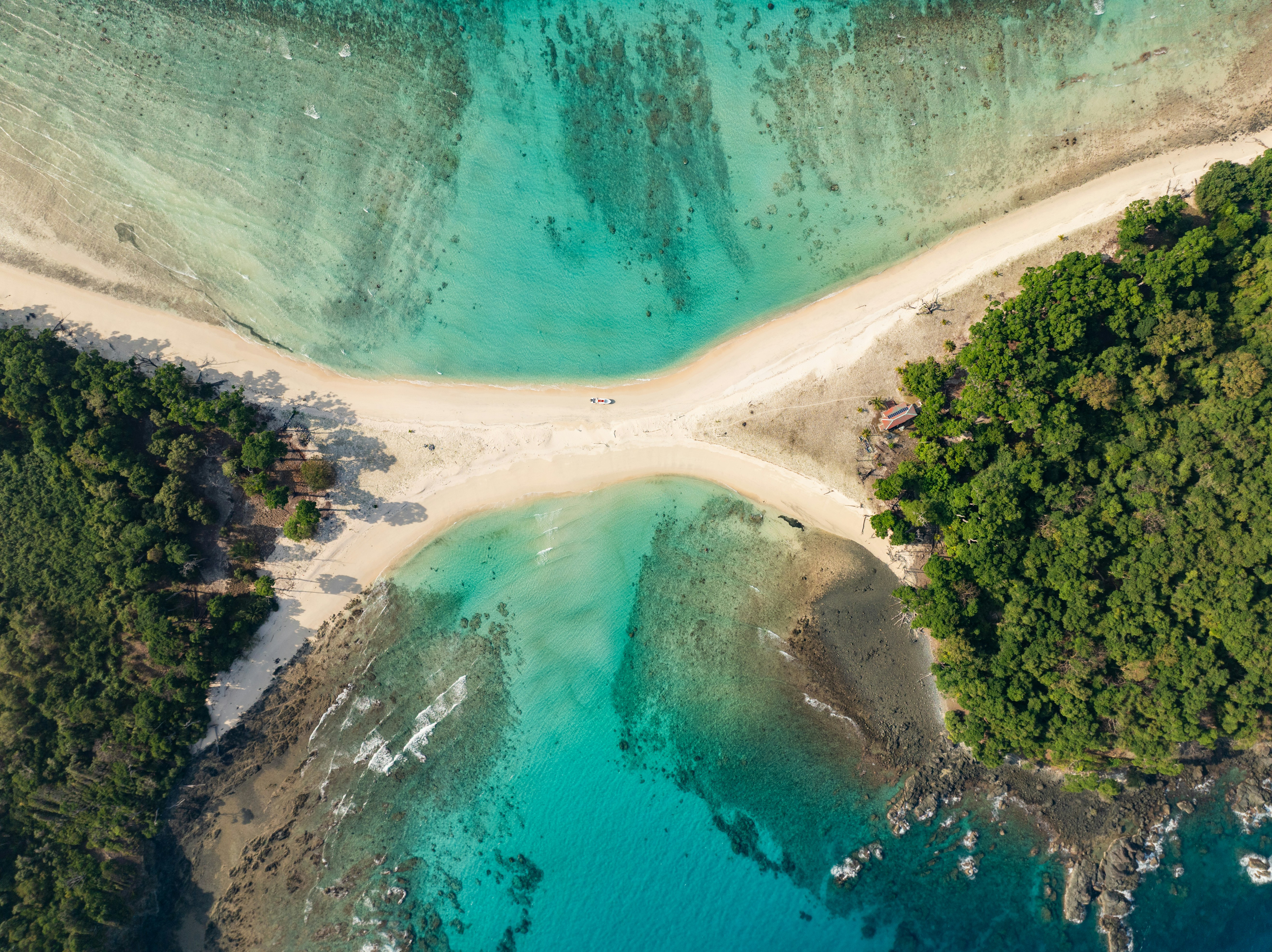 White sandbar divides turquoise ocean and green tropical islands.