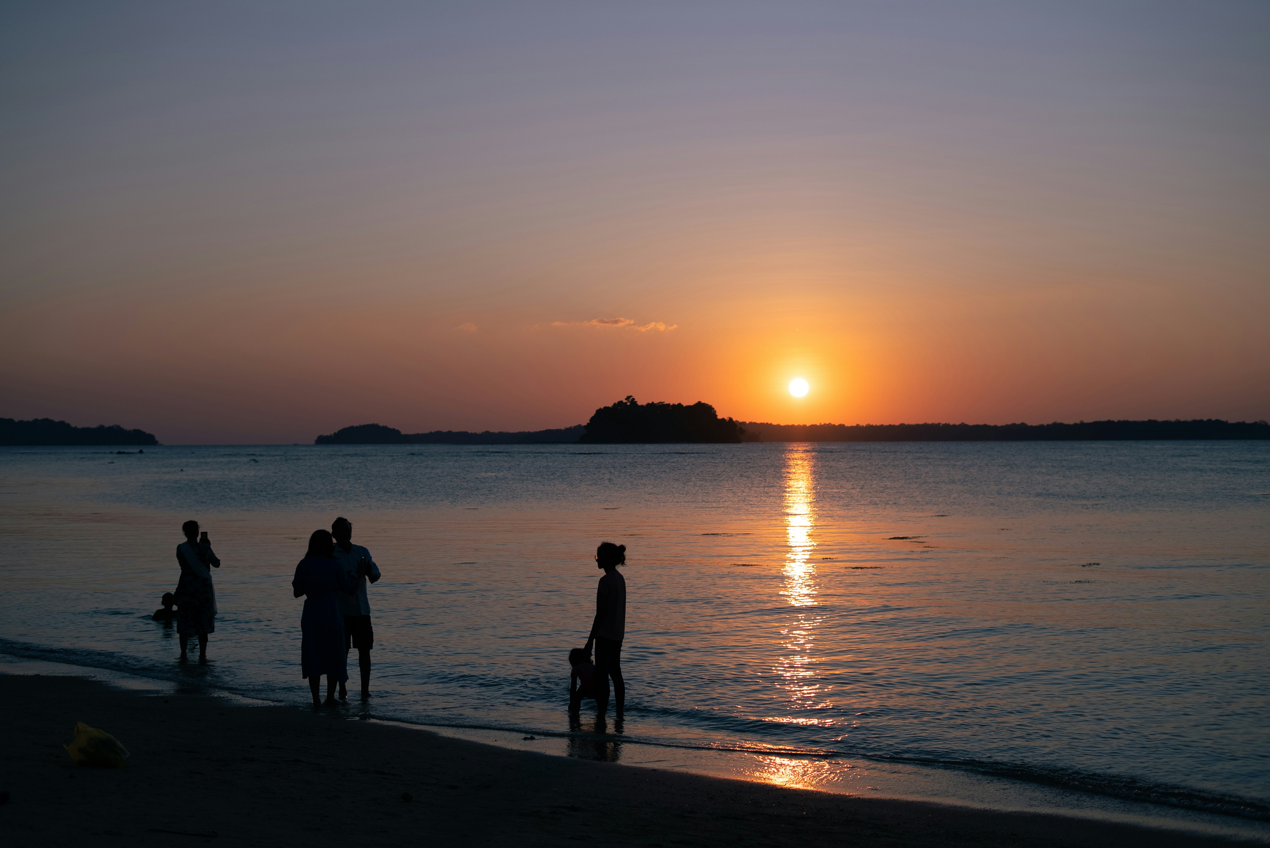 Sunset Silhouette: Children and Figures on a Quiet Shore