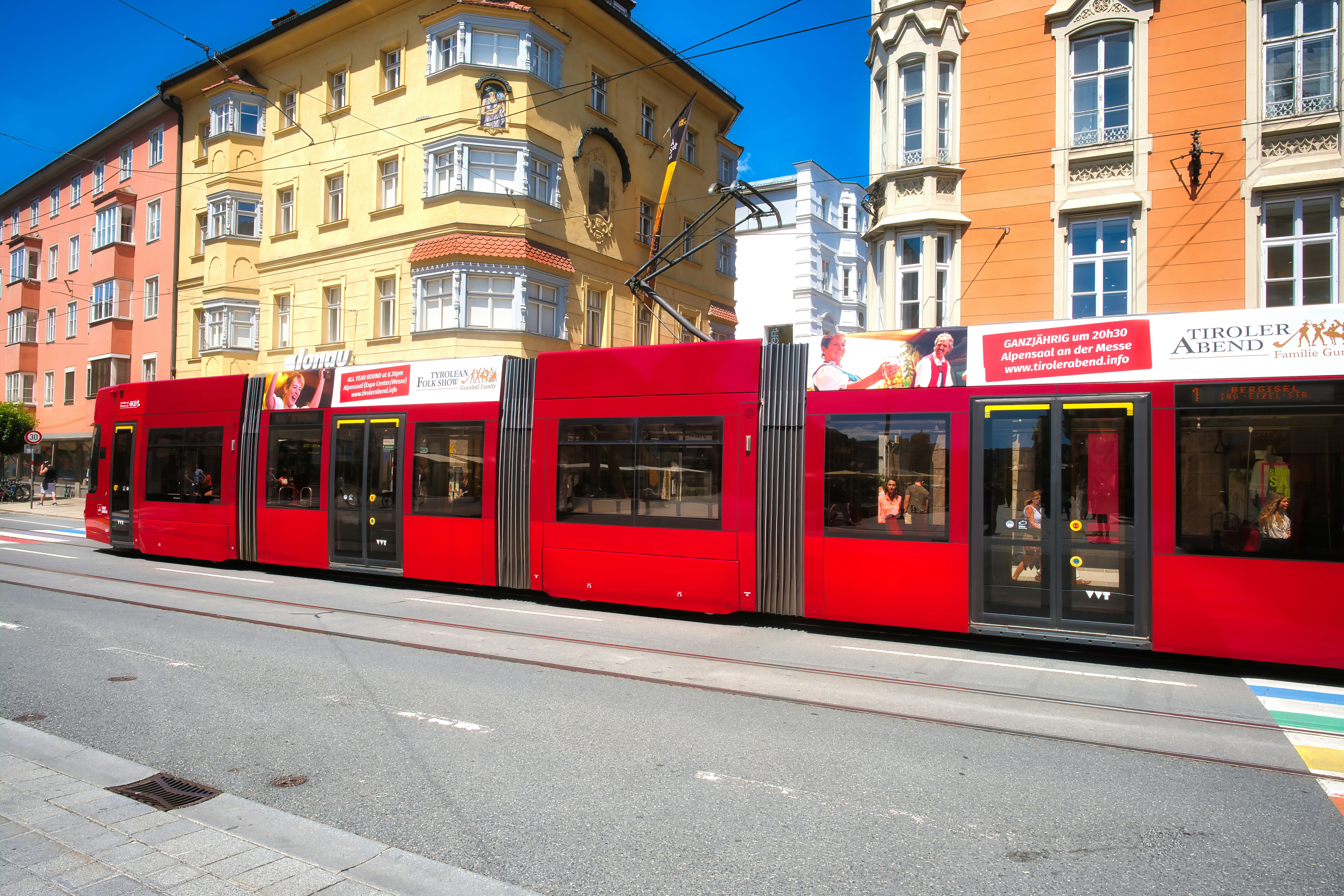 Red Transit Gliding Past Colorful City Facades