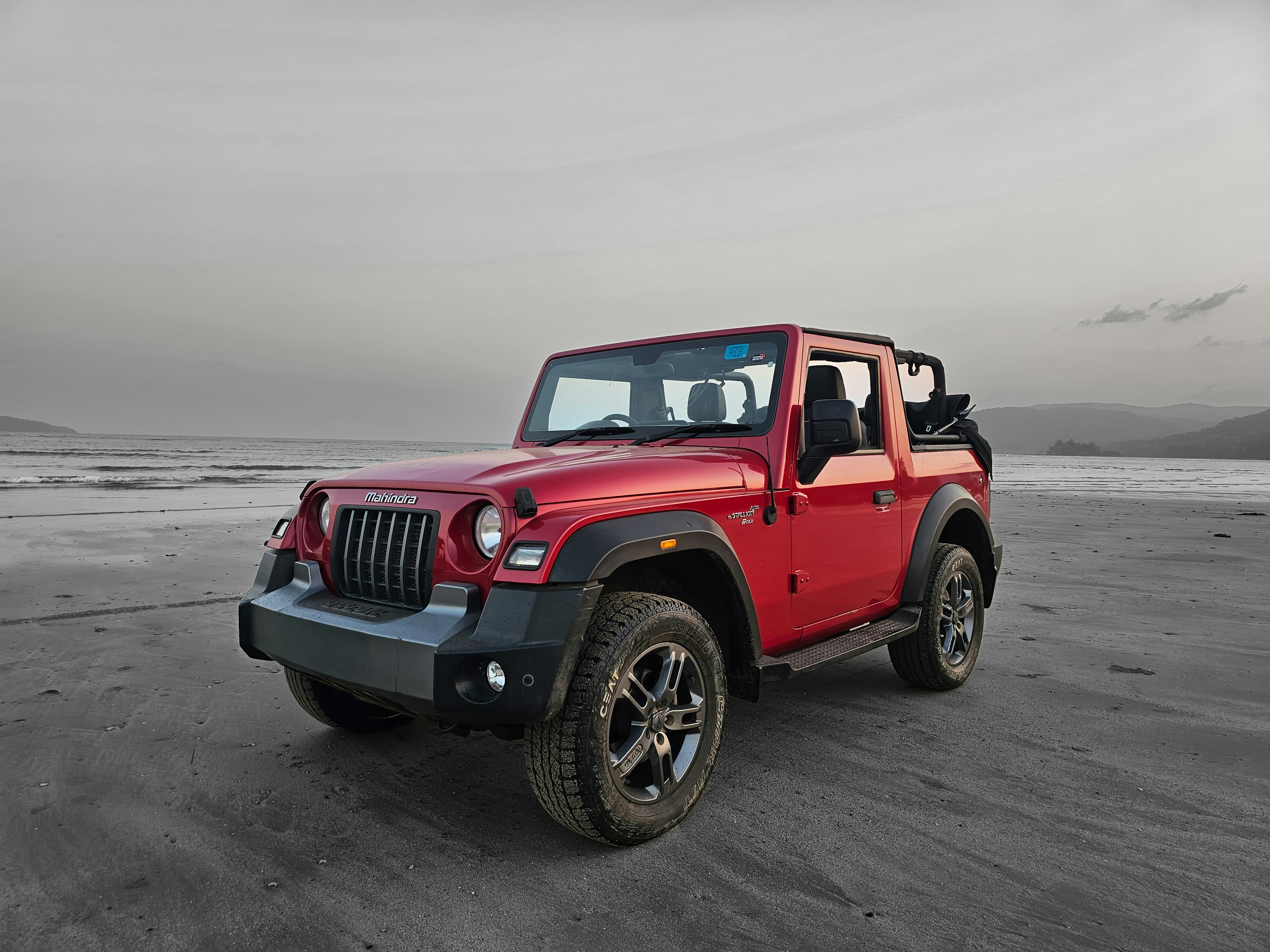 A red off-road vehicle parked on a sandy beach.