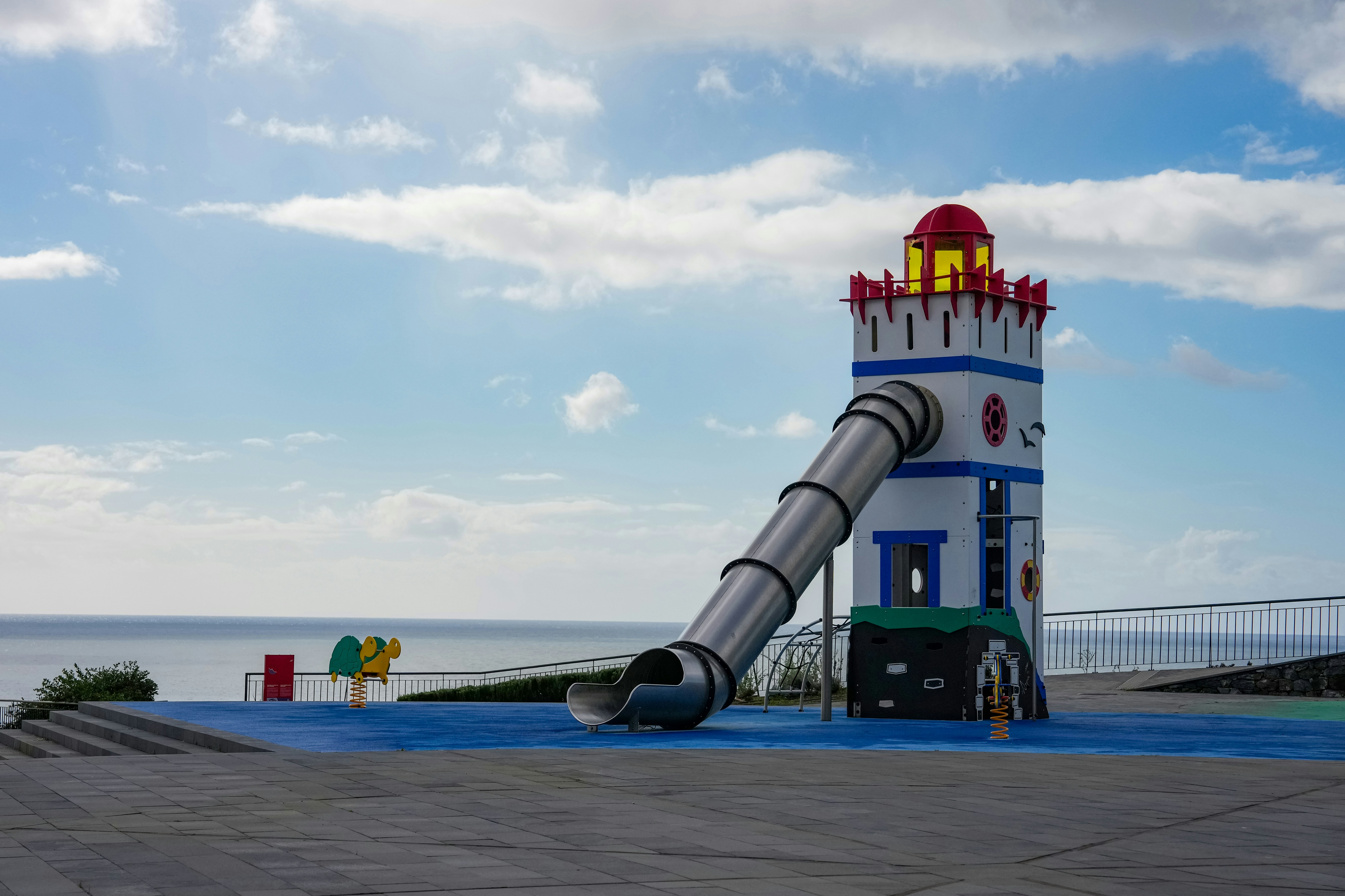 Lighthouse playground slide overlooking the calm ocean.