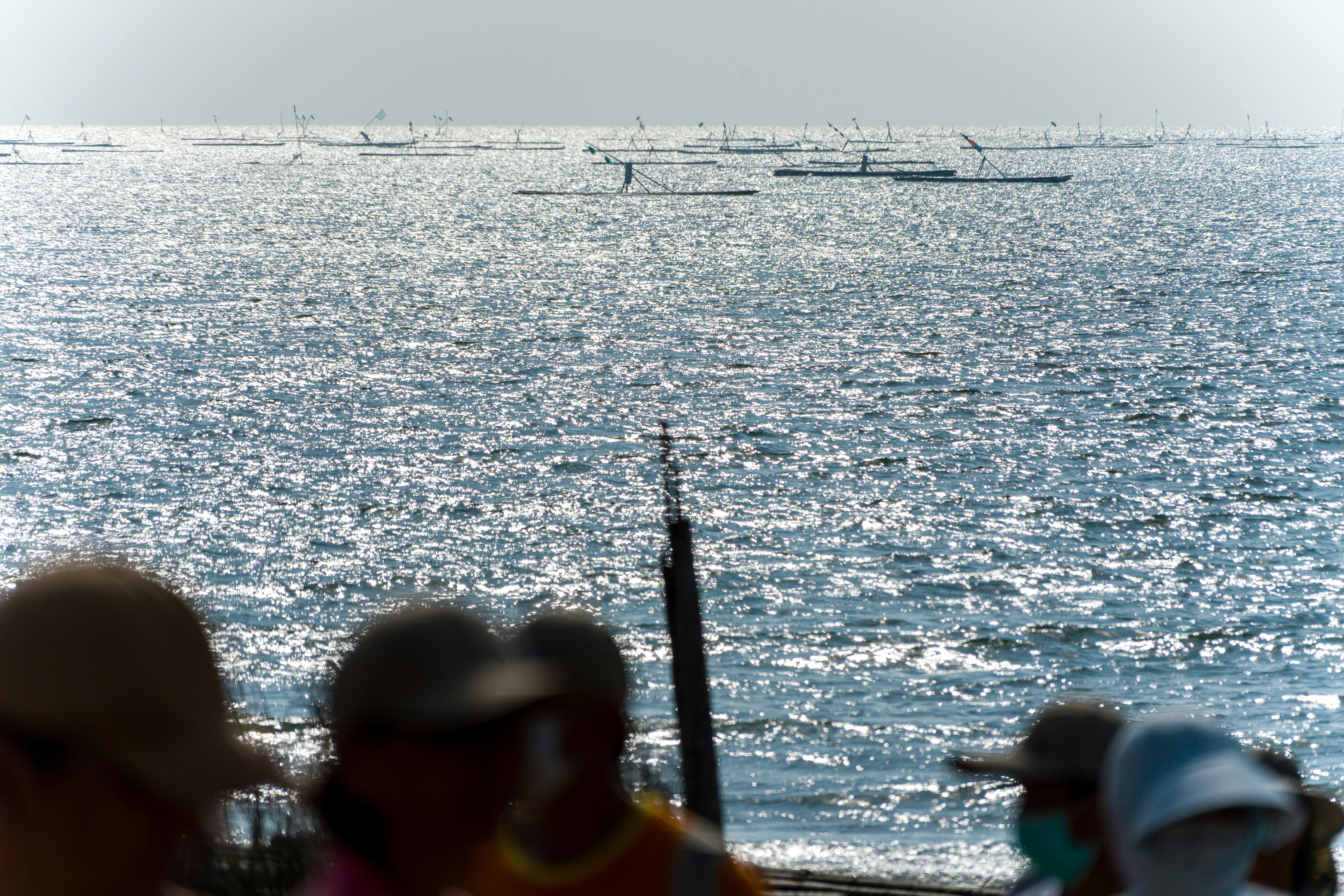 Bright sparkling ocean with distant boats and blurred foreground.