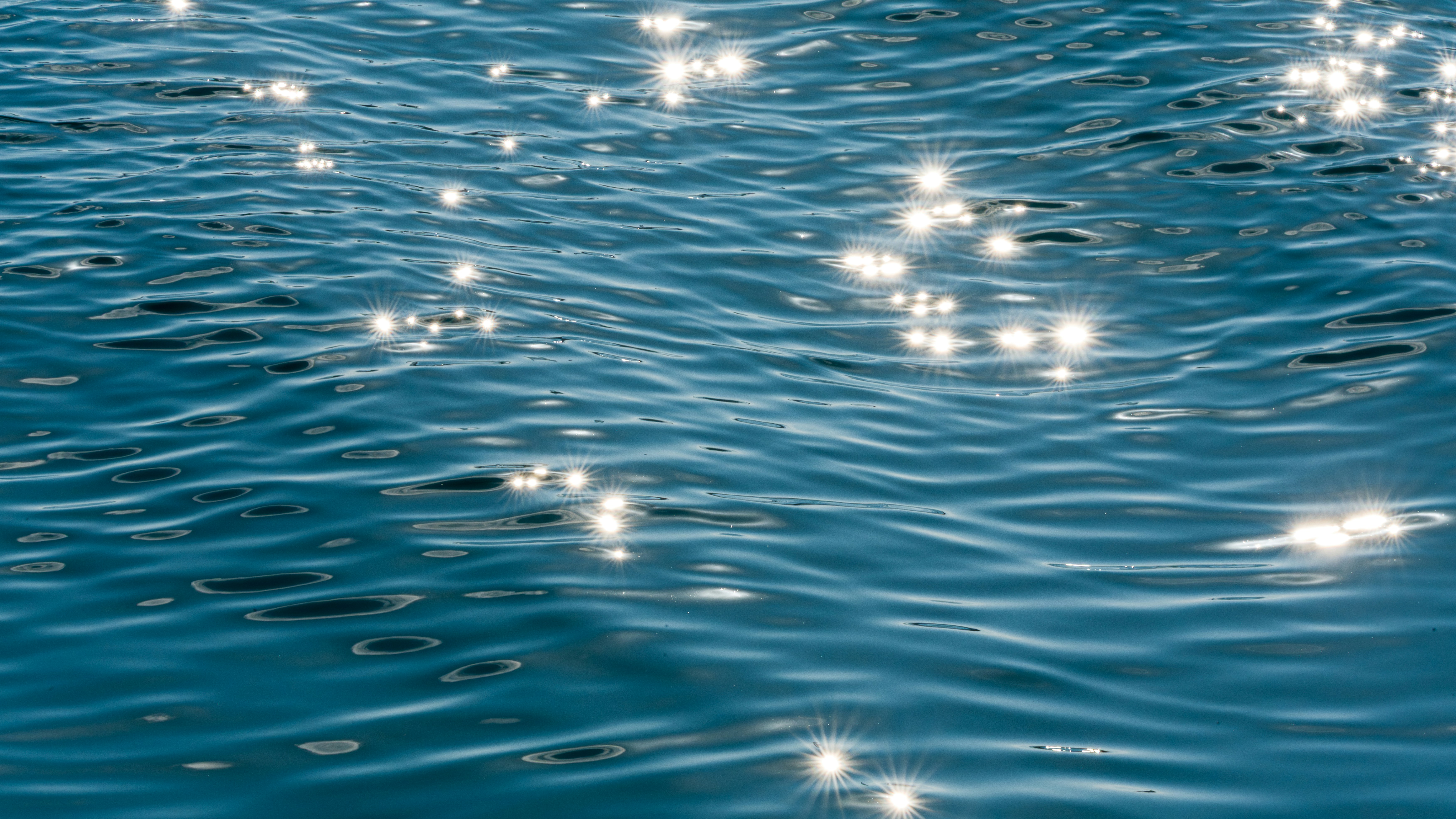 Glittering Ripples: A Sunlit Sea Surface in Calm Wake