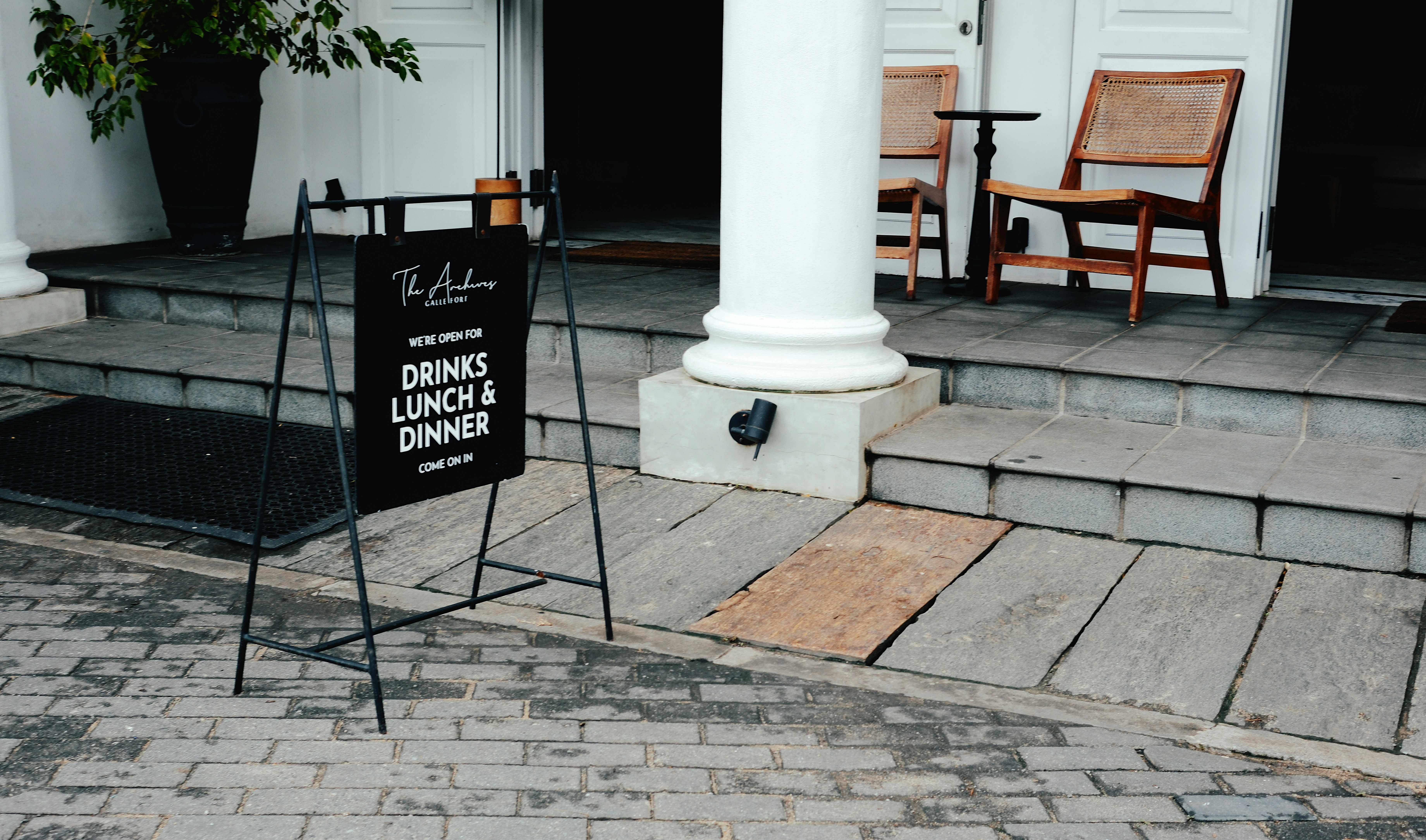 Silent Entrance: A Café Signboard Framed by Steps and Chairs