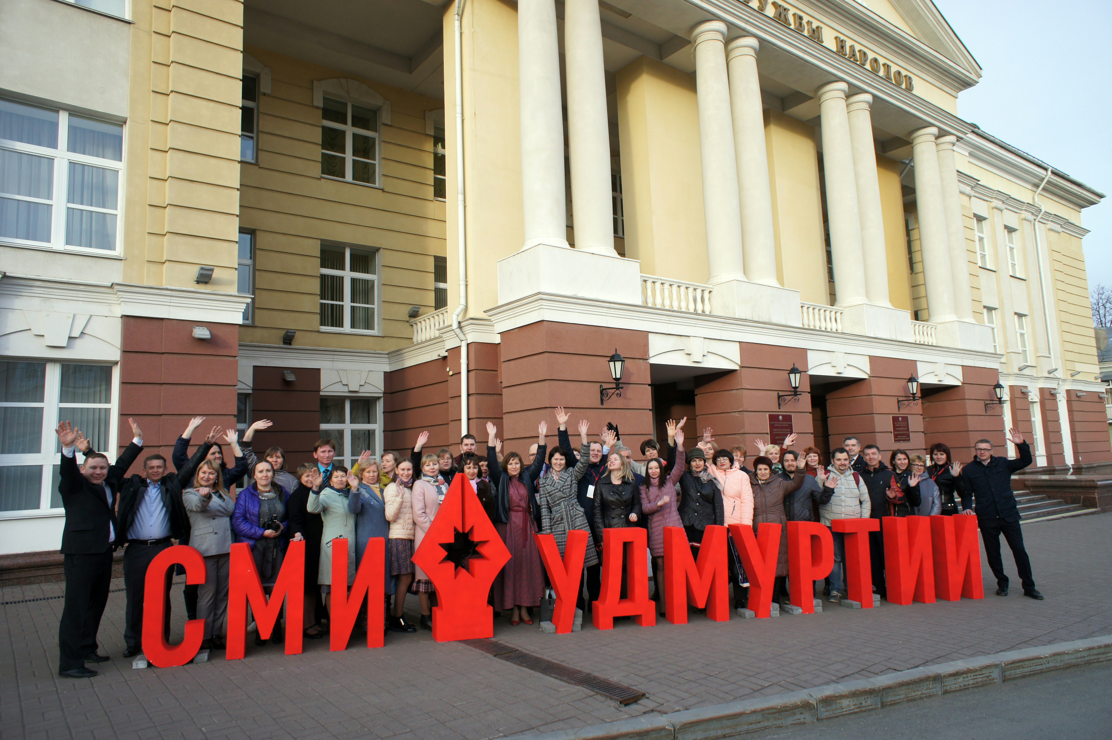 Group Portrait in Front of a Historic Building with Bold Red Letters