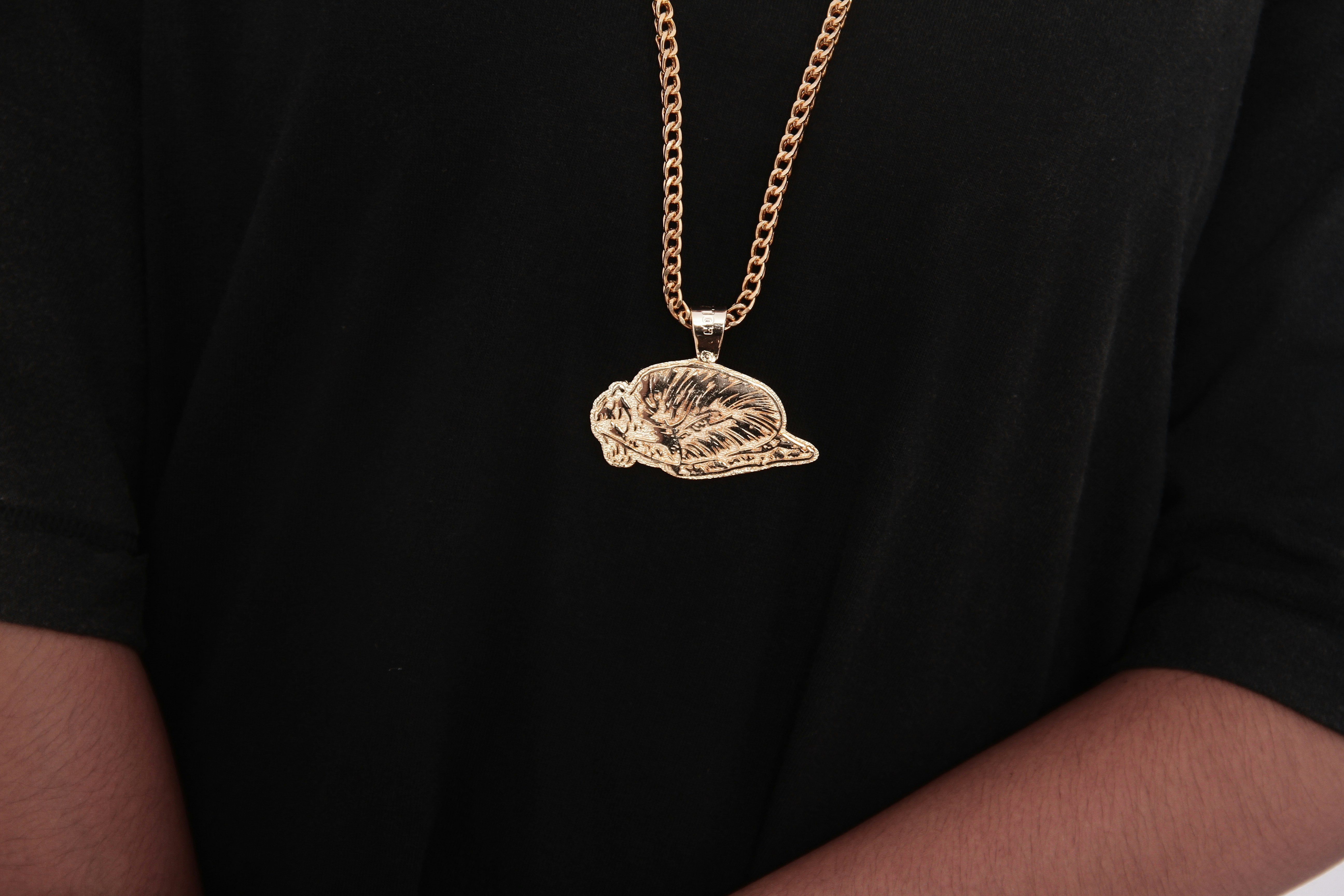Gold Chain Pendant resting over a dark tee