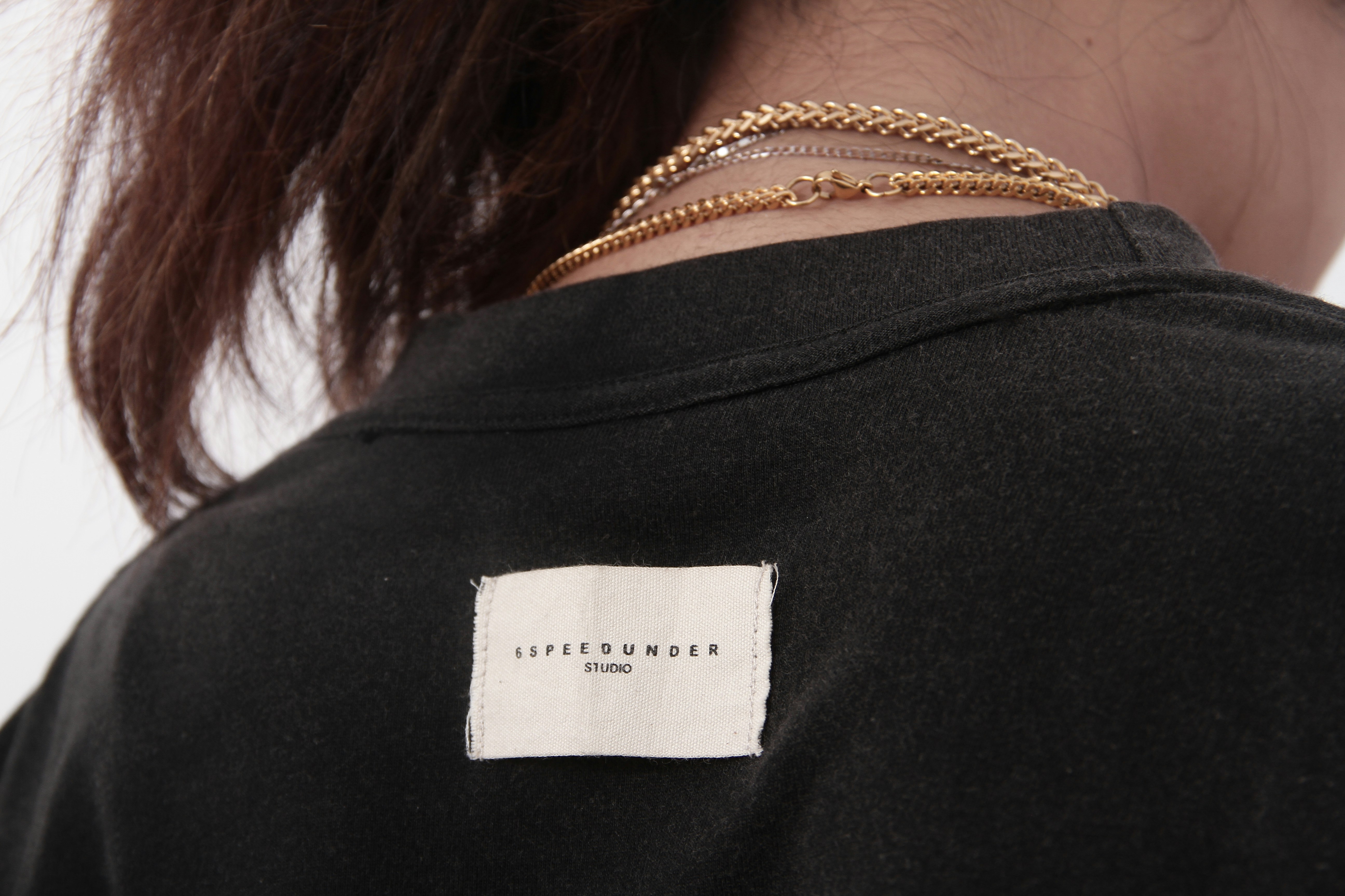 Label on the Back: Subtle Brand Detail Framed by Hair and Chains