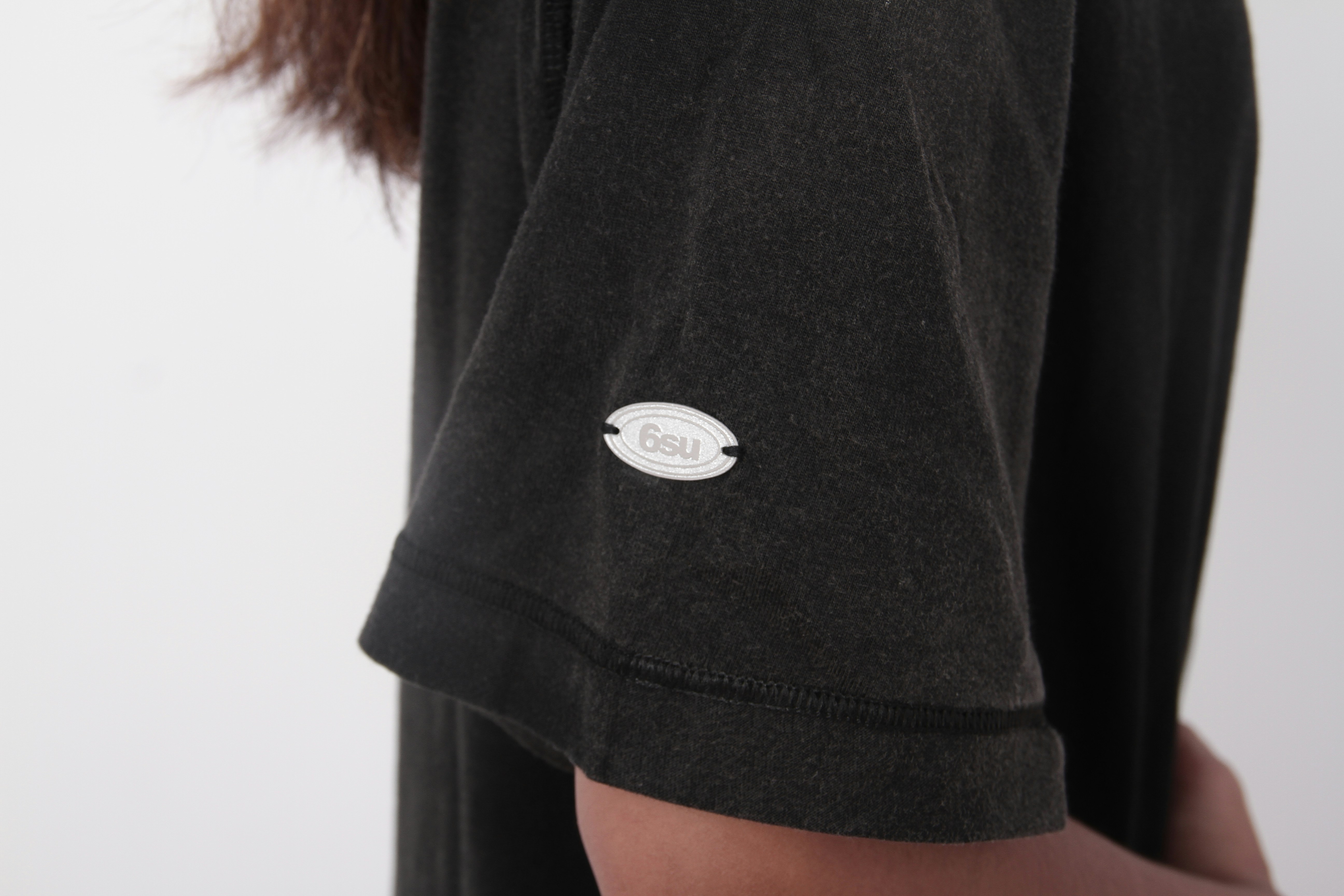 Close-up of a dark tee sleeve with a small logo peeking into the frame