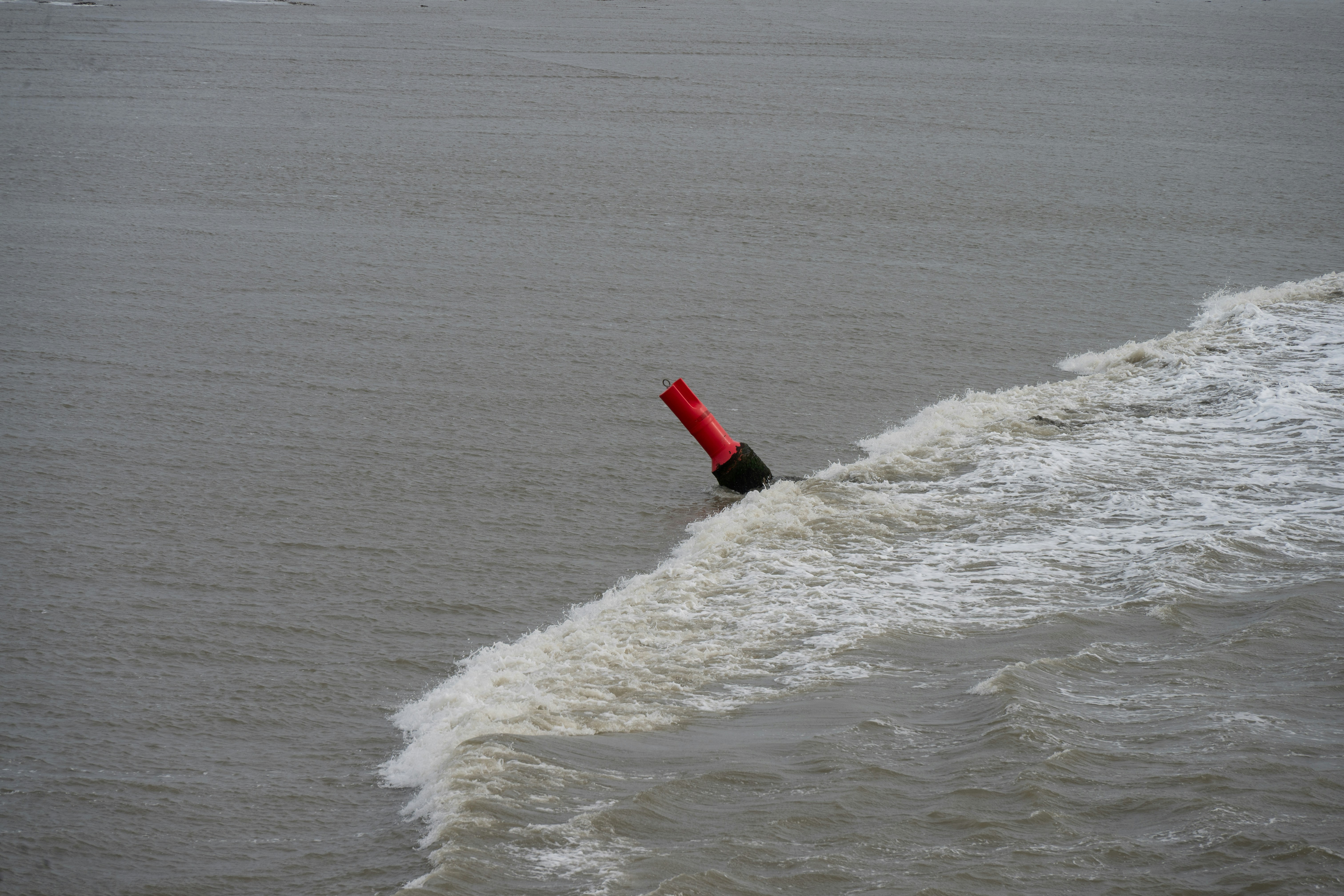 Red Buoy Pauses the Tide: A lone rescue buoy surfacing from the waves