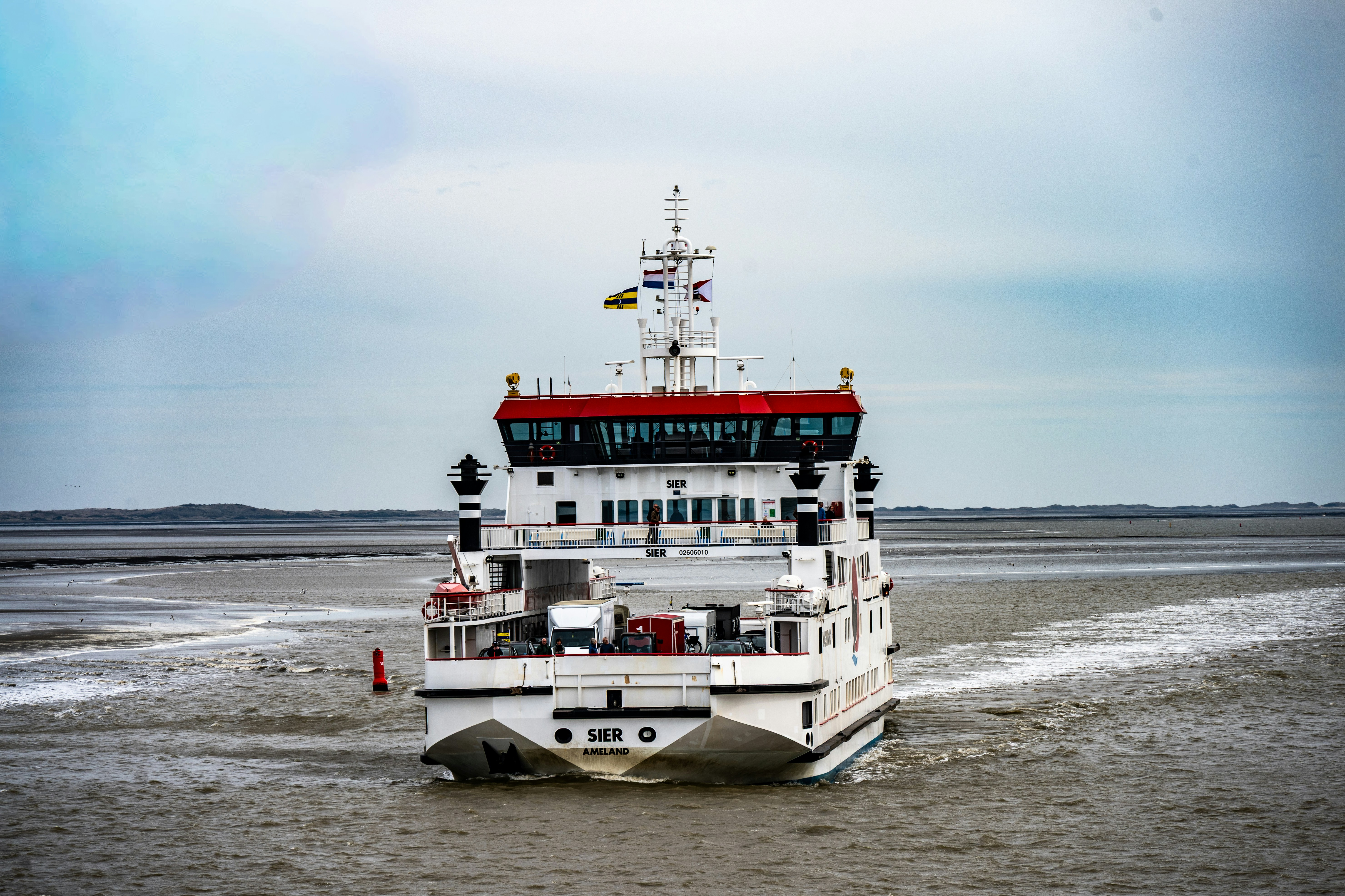 A white ferry boat sailing in shallow water.
